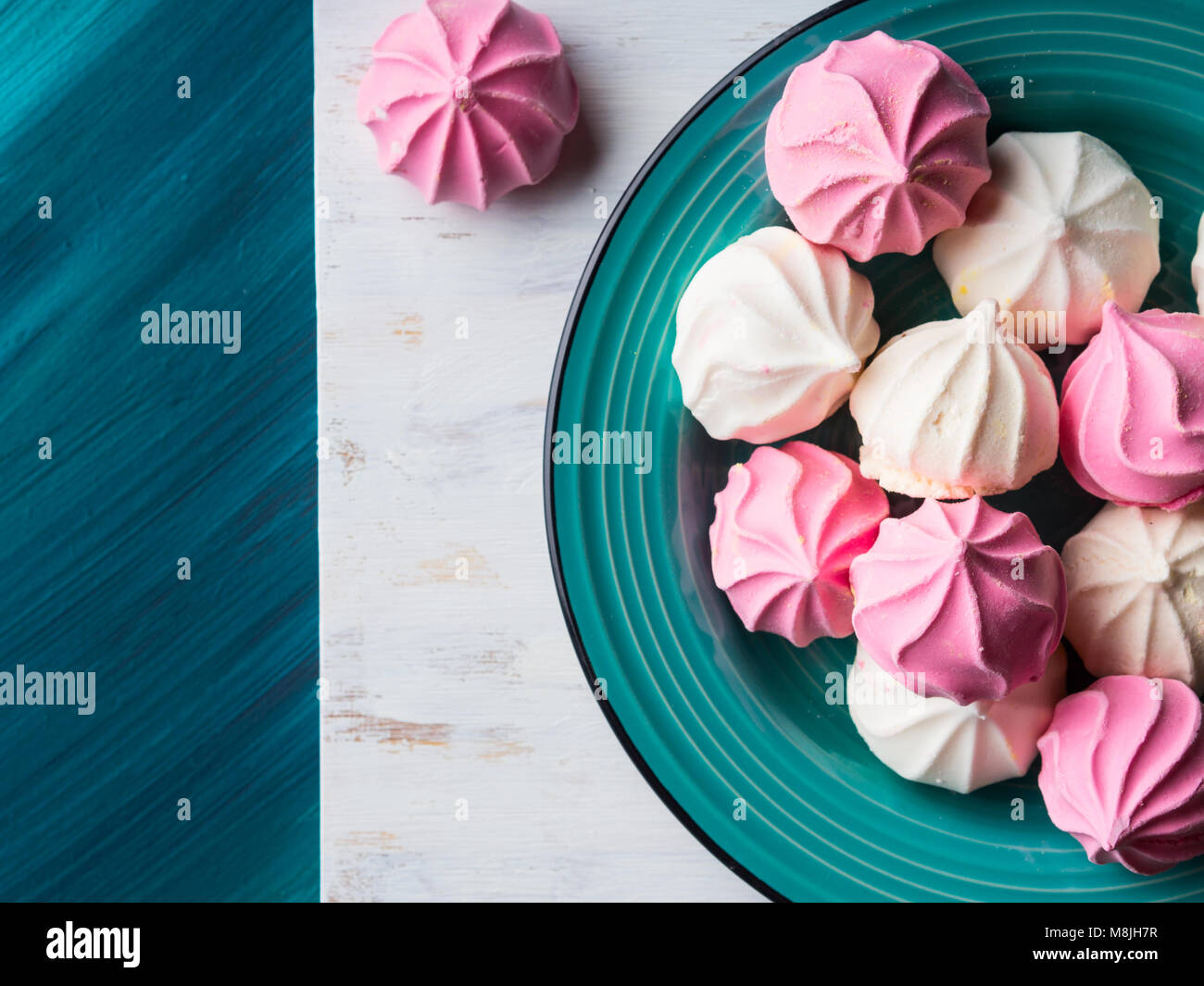 Pastel color pink and white meringue on green background Stock Photo ...