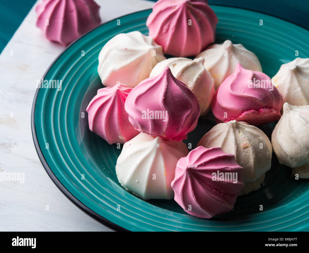 Pastel color pink and white meringue on green background Stock Photo ...