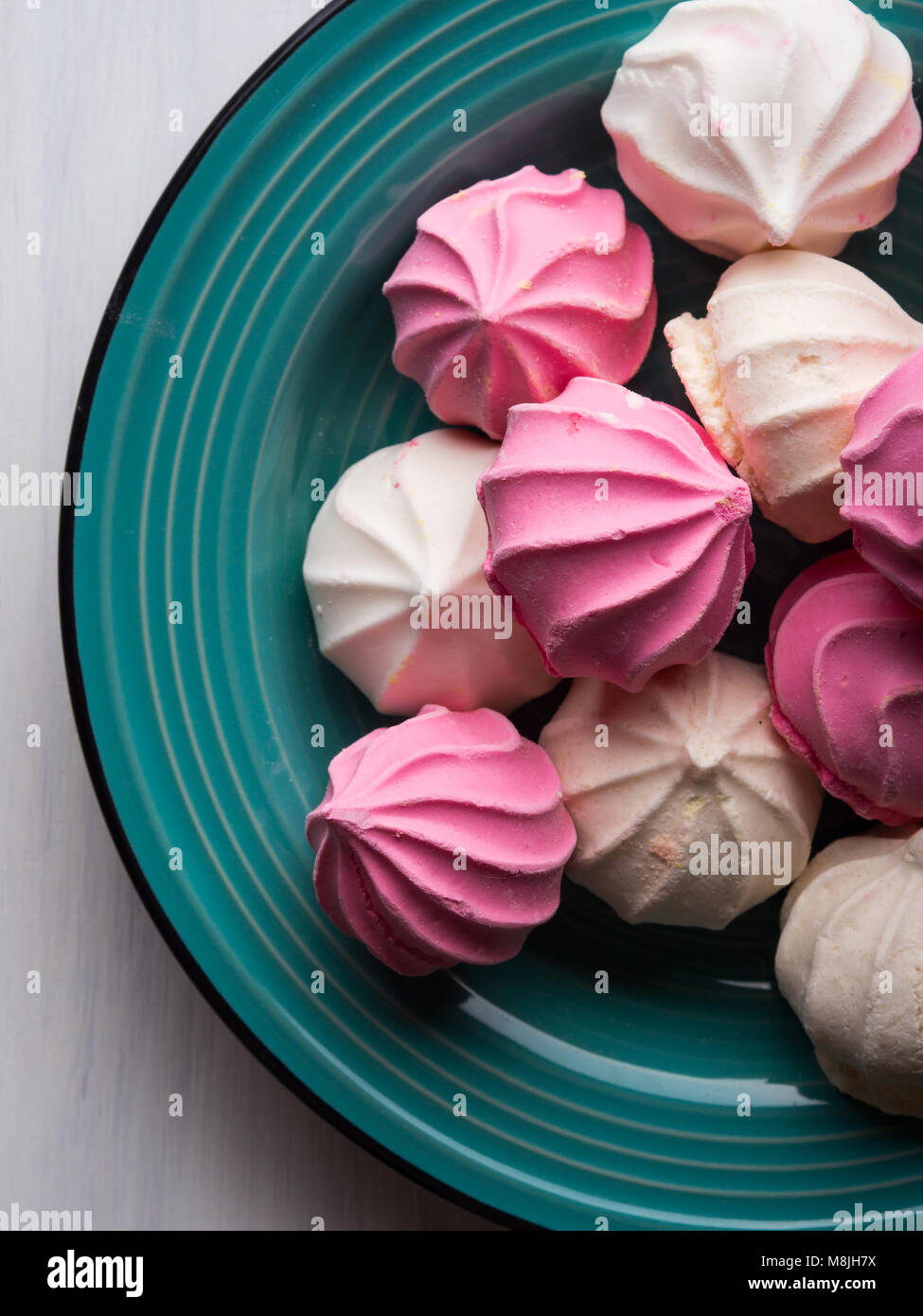 Pastel color pink and white meringue on green background Stock Photo ...
