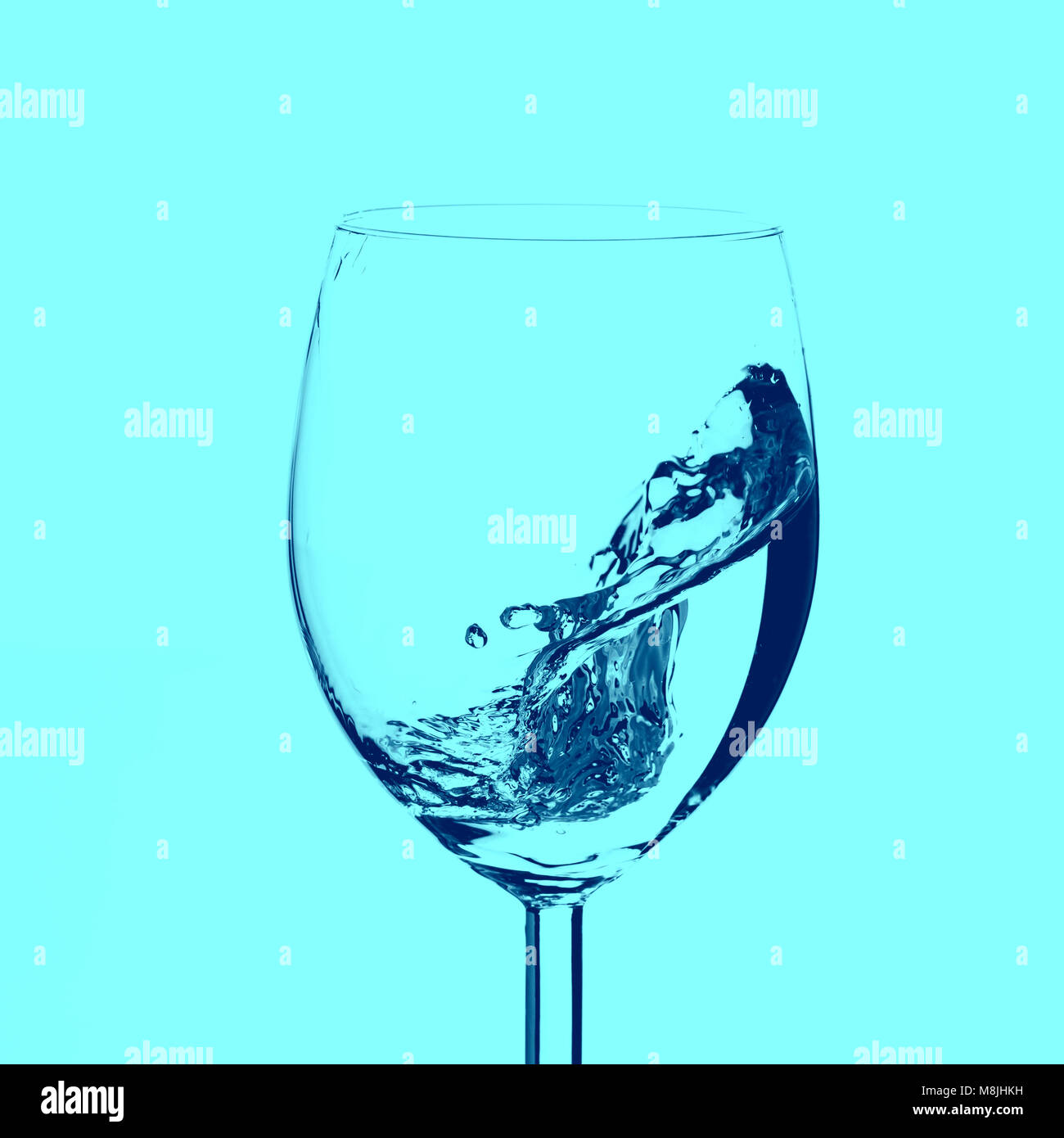 Half empty glass with water splashes in motion on white background ...
