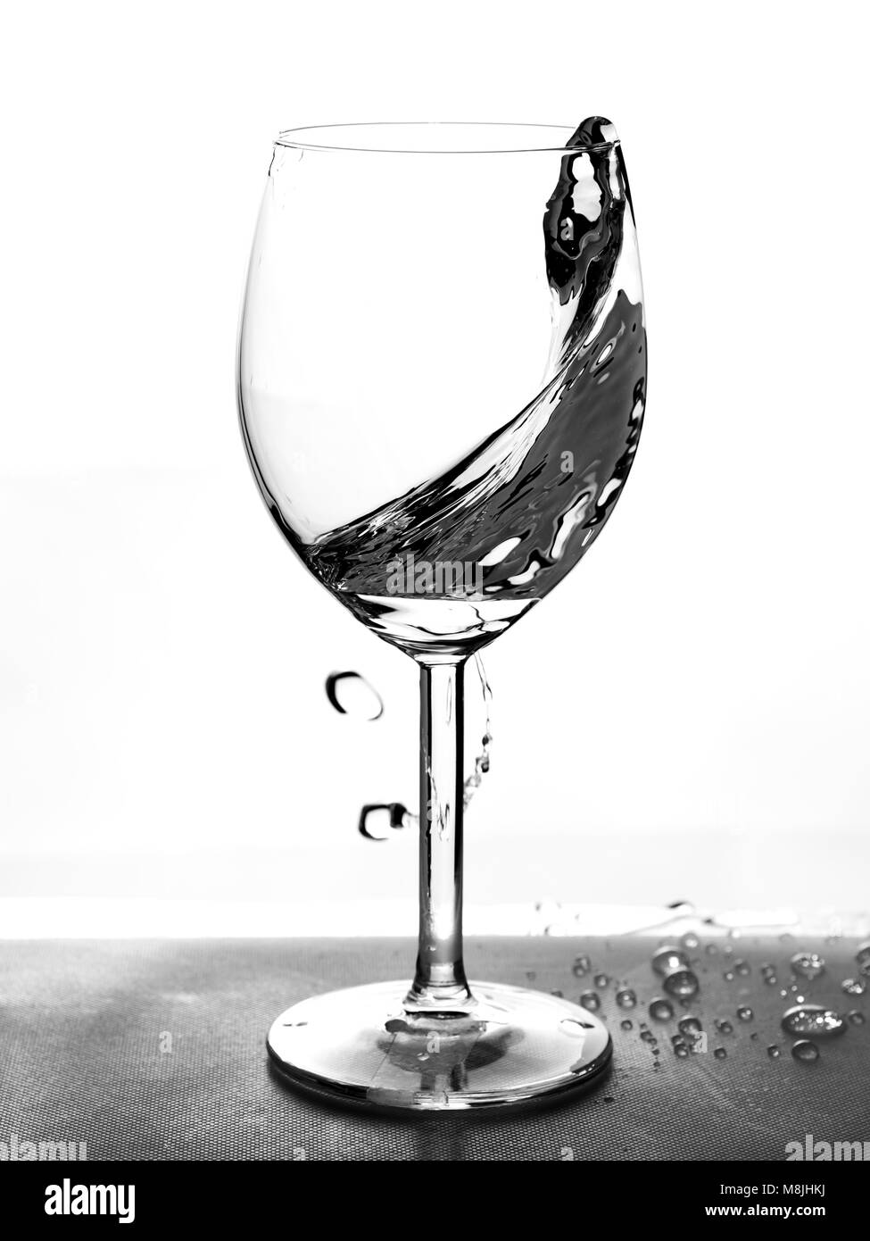 Half empty glass with water splashes in motion on white background ...