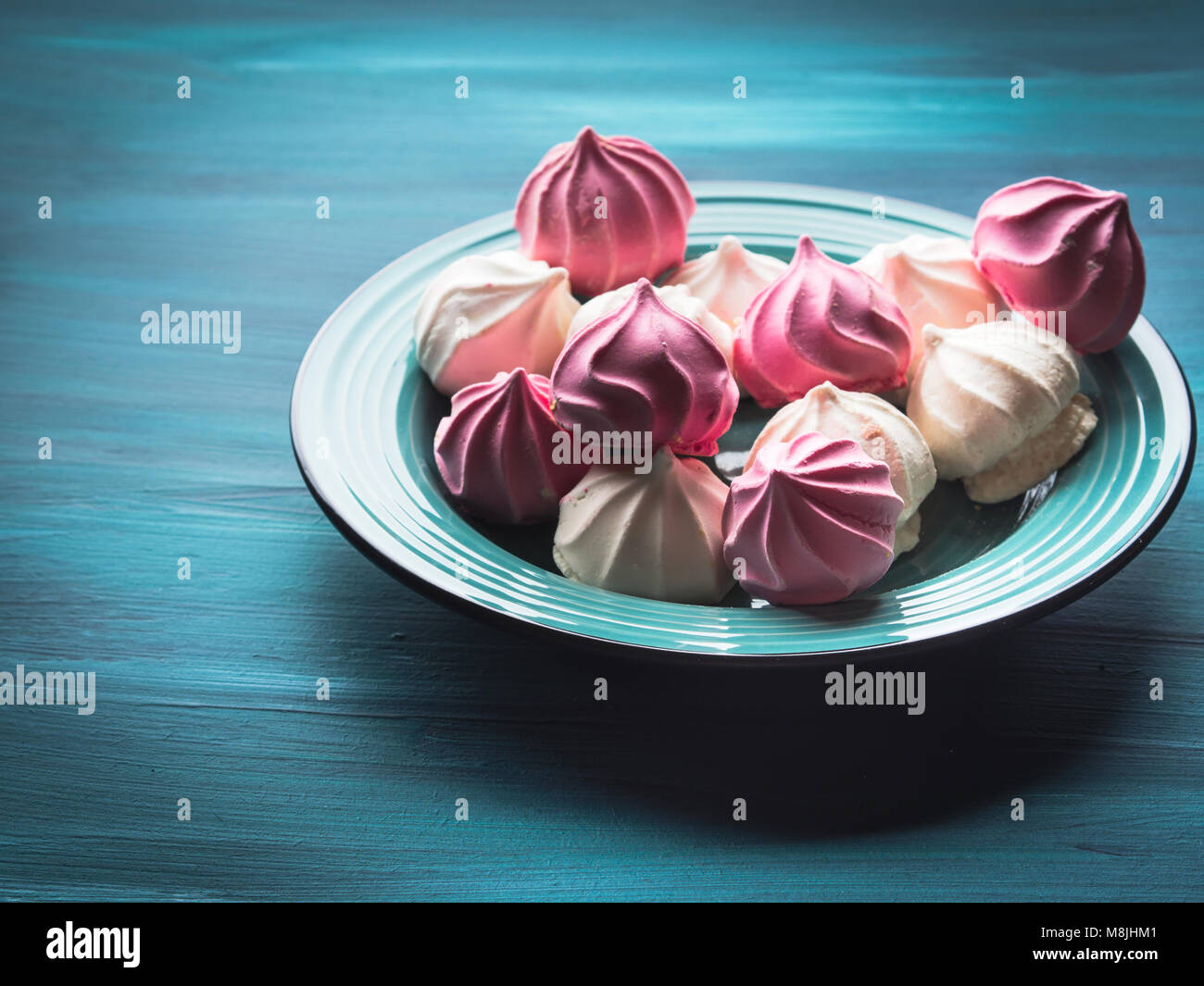 Pastel color pink and white meringue on green background Stock Photo ...