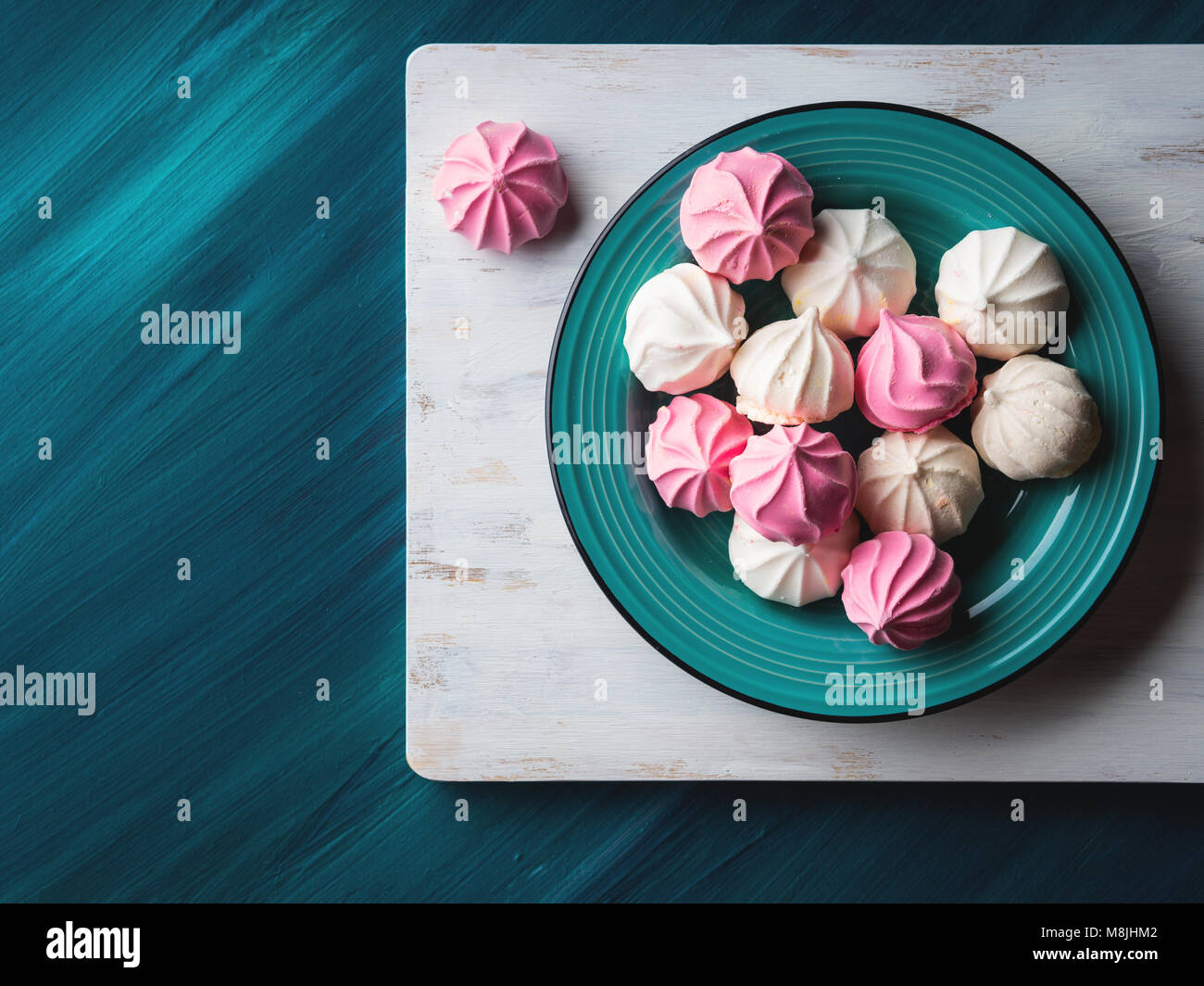 Pastel color pink and white meringue on green background Stock Photo ...