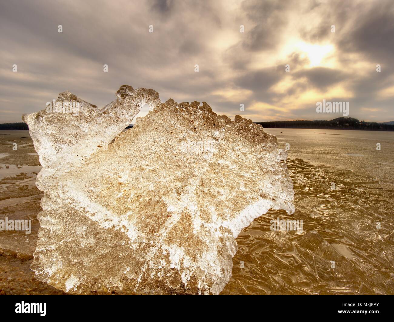 Icy sheets melting on sandy beach. End of long and crue winter coming ...