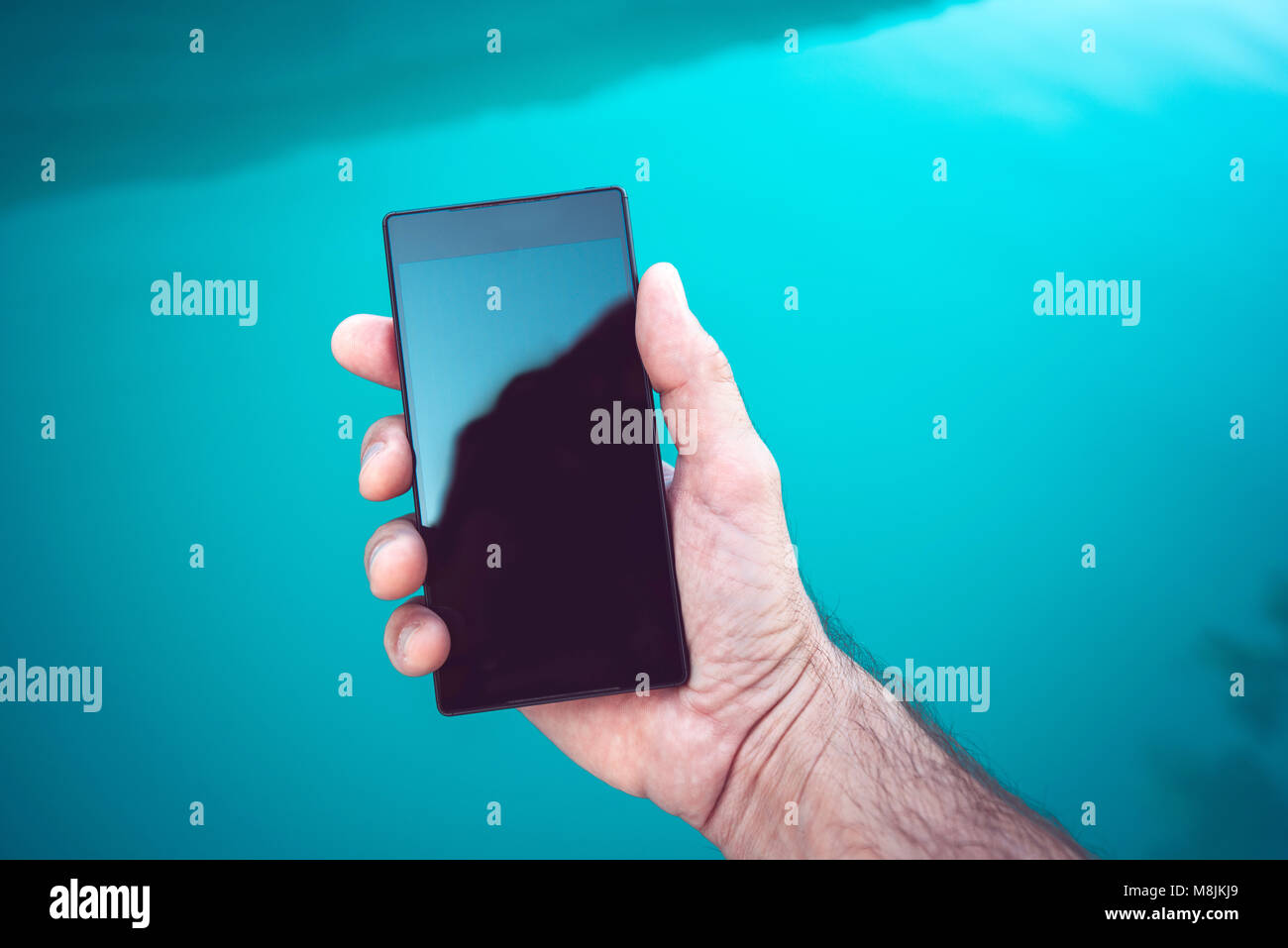 Using mobile phone by the swimming pool, male hand holding smartphone ...