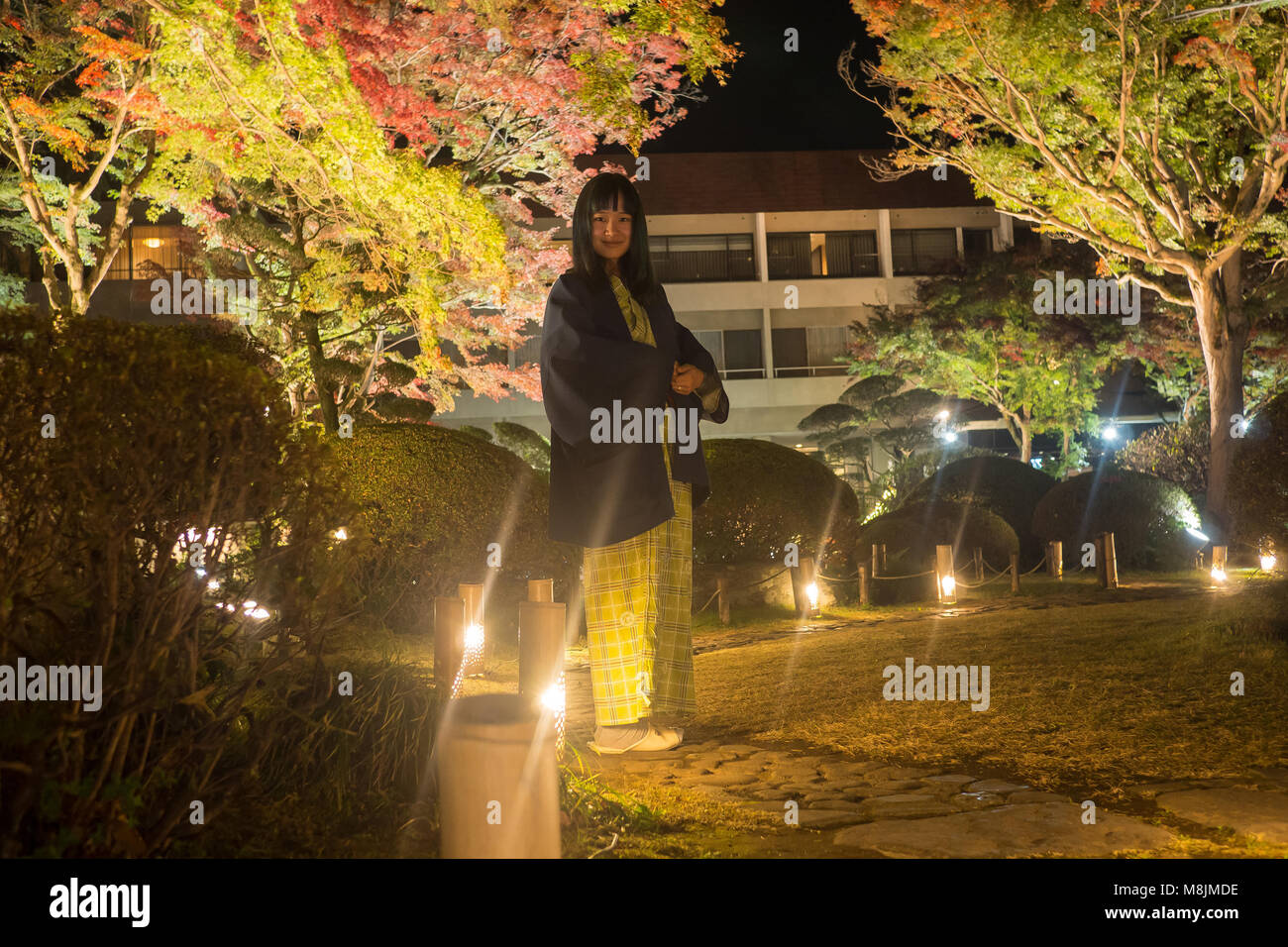 Beautiful young woman in a Yukata strolling through a japanese garden ...