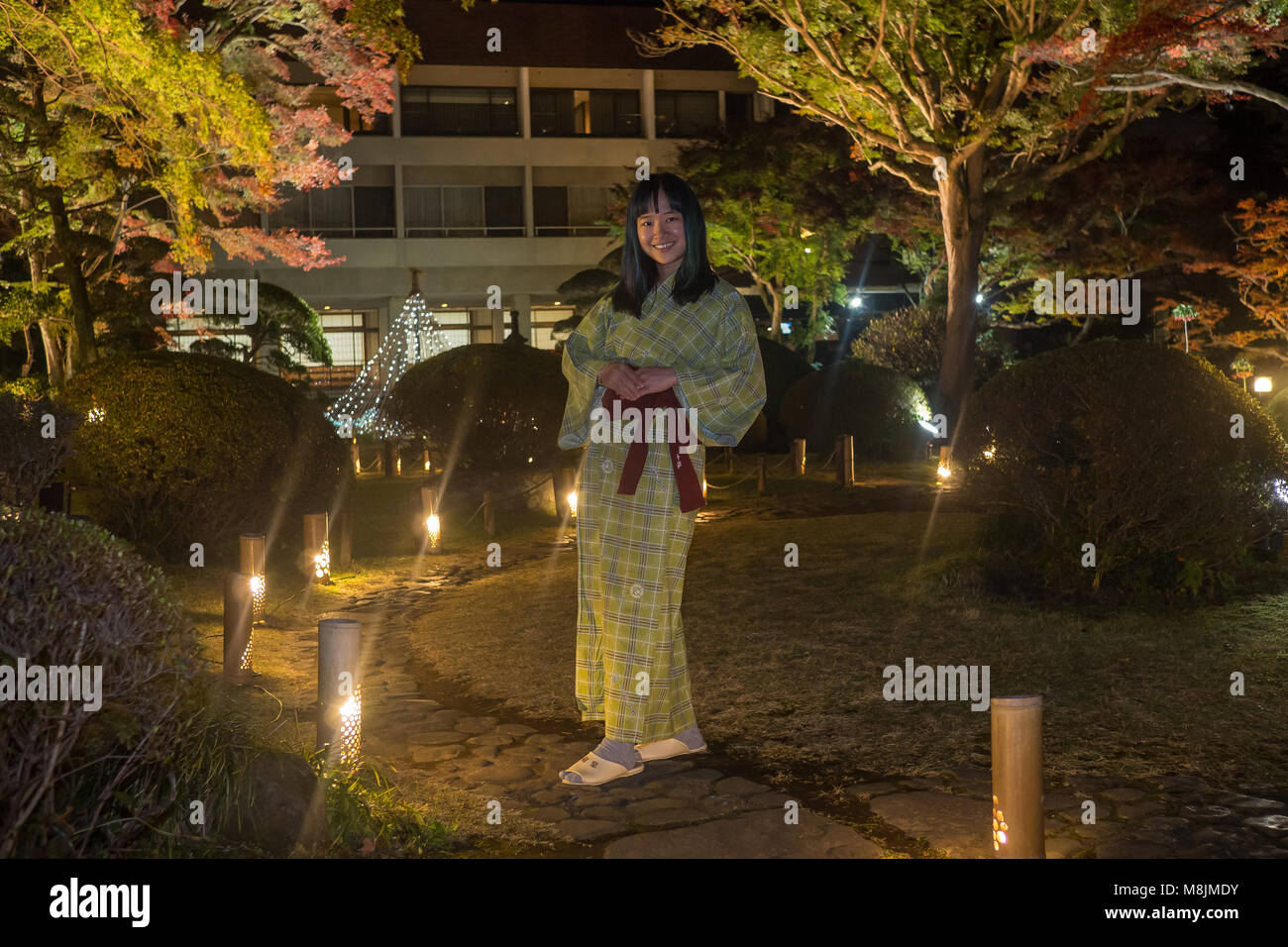 Beautiful young woman in a Yukata strolling through a japanese garden ...