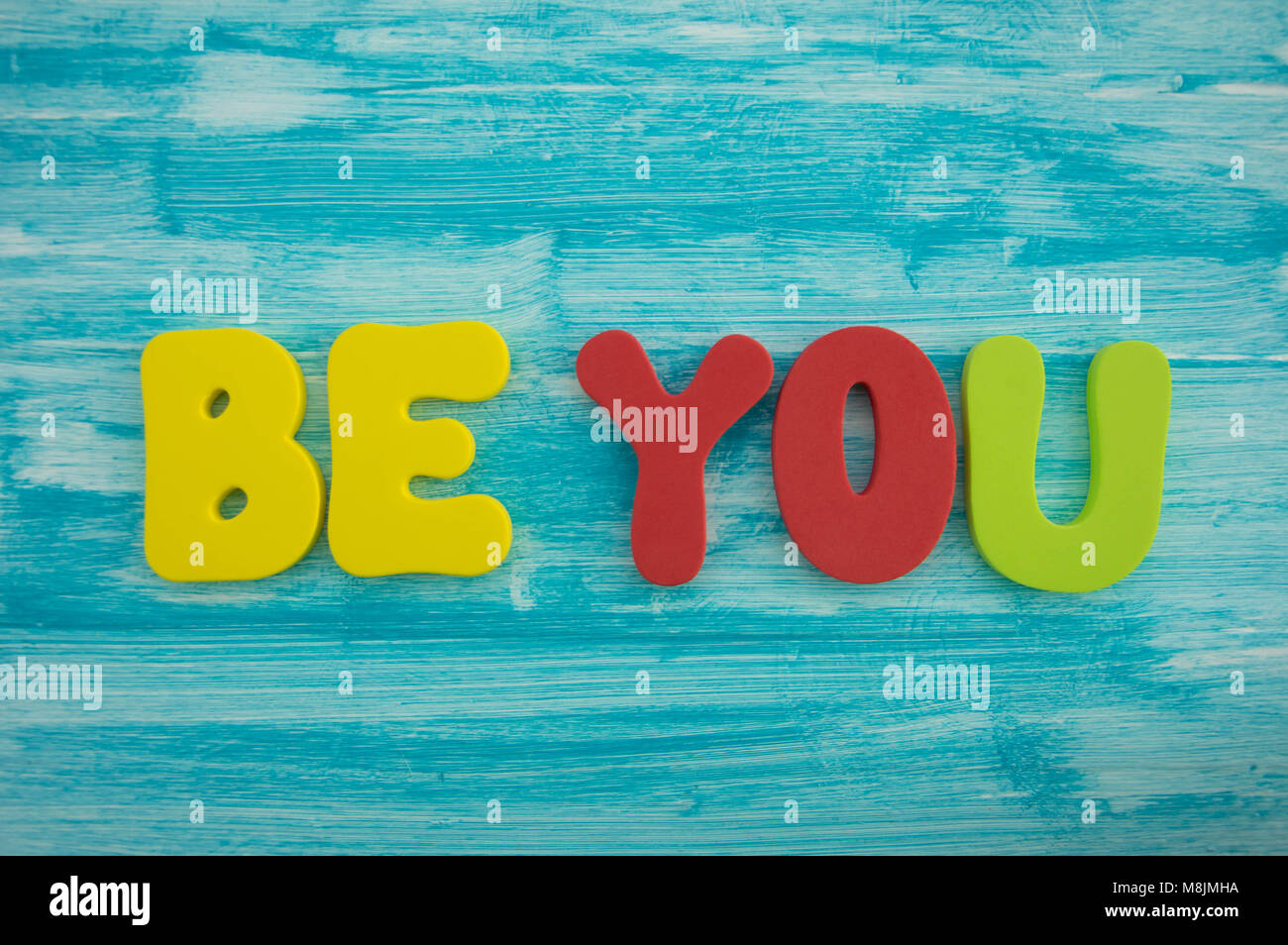Be You in capital letters on blue colour wash wood background Stock ...