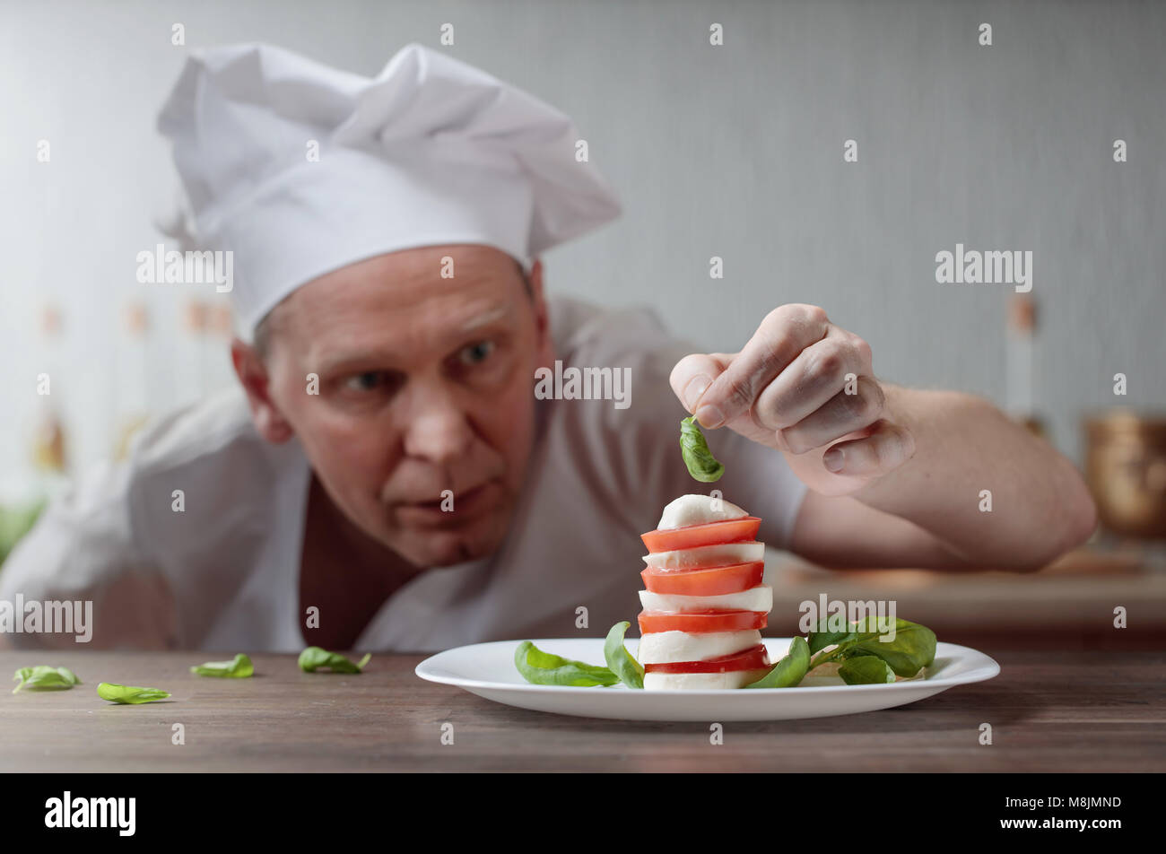 Chef prepares a snack with mozzarella , tomatoes and basil . Selective ...