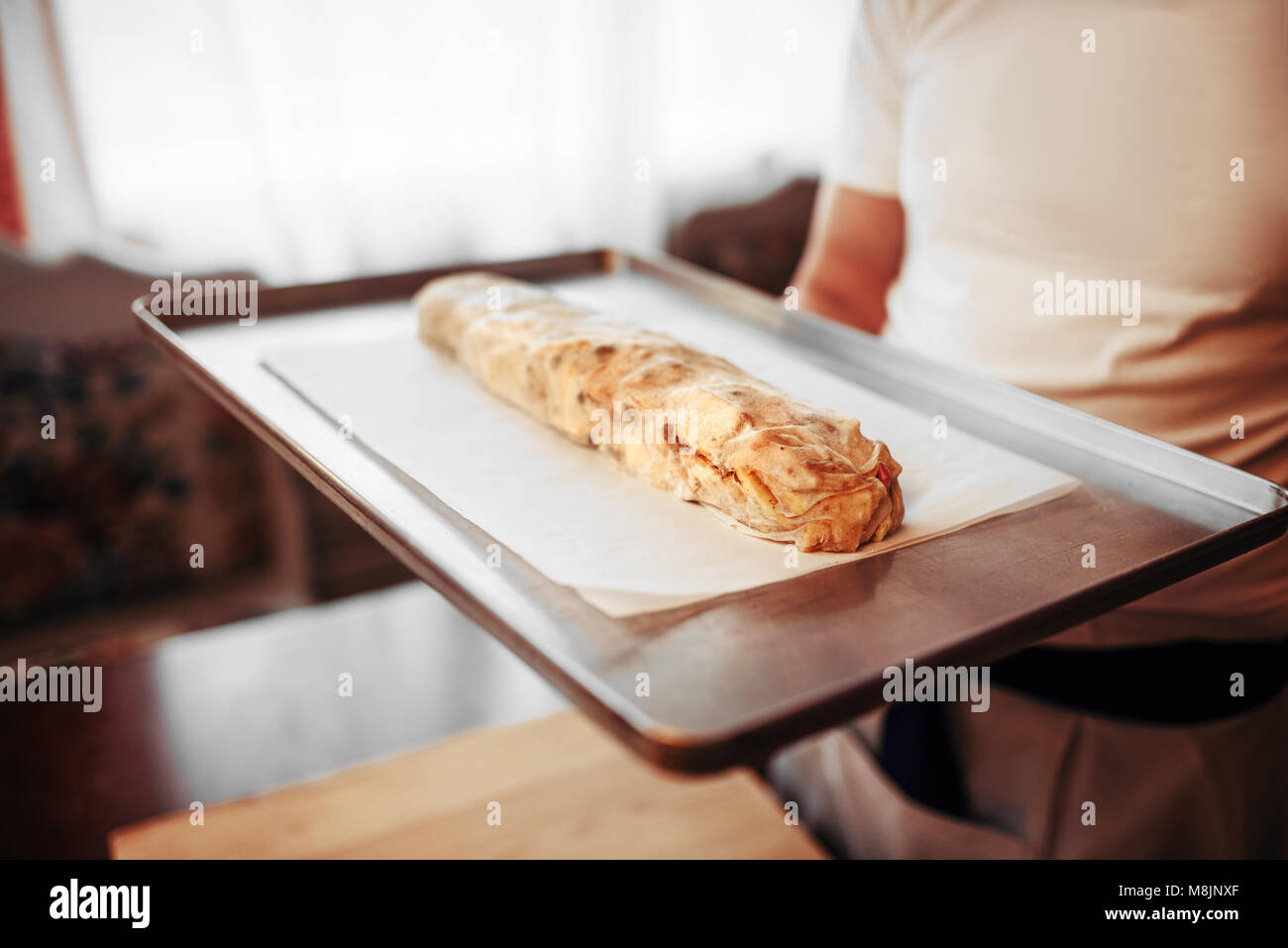 Male chef holds metal baking sheet with classical apple strudel, bakery ...
