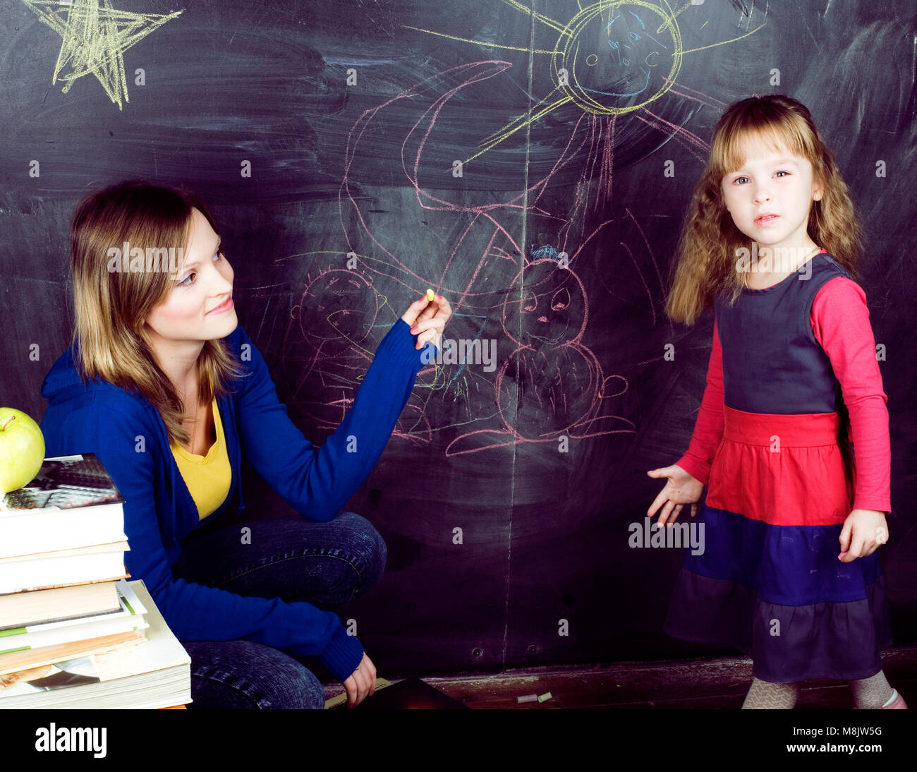 portrait of woman and little cute girl painting on blackboard Stock ...