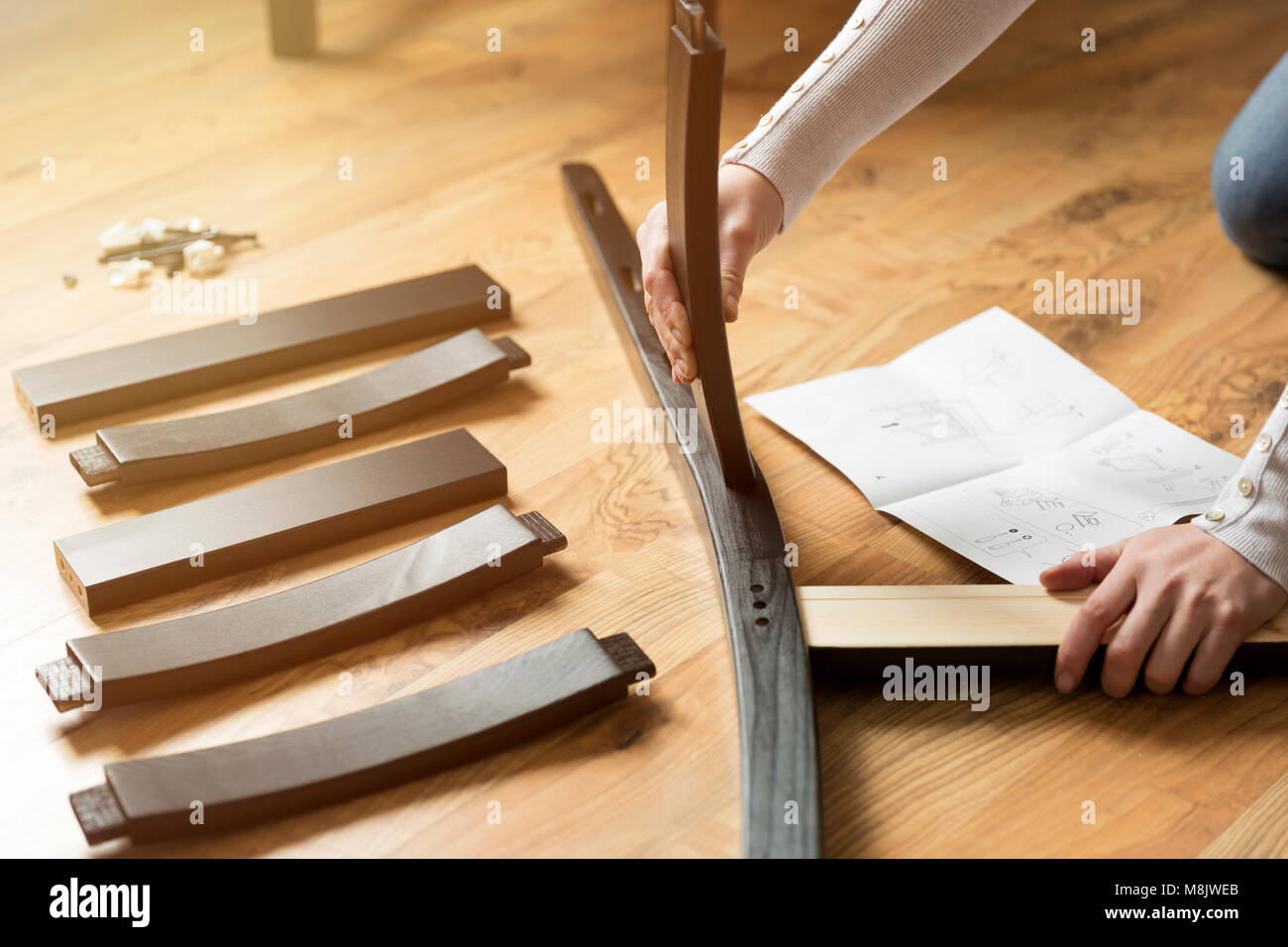 Assembly of wooden furniture, a woman putting together the wooden parts ...