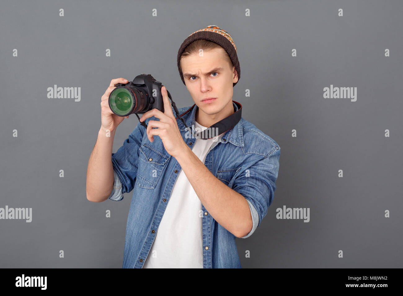 Young guy photographer wearing jeans jacket and hat studio isolated on ...