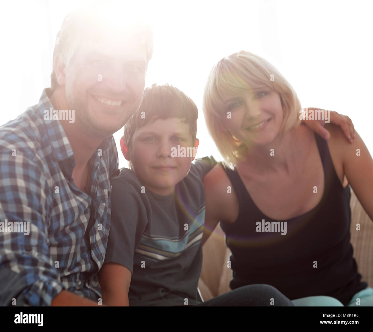 Parents and their son sit huddled in the living room and smiling Stock ...