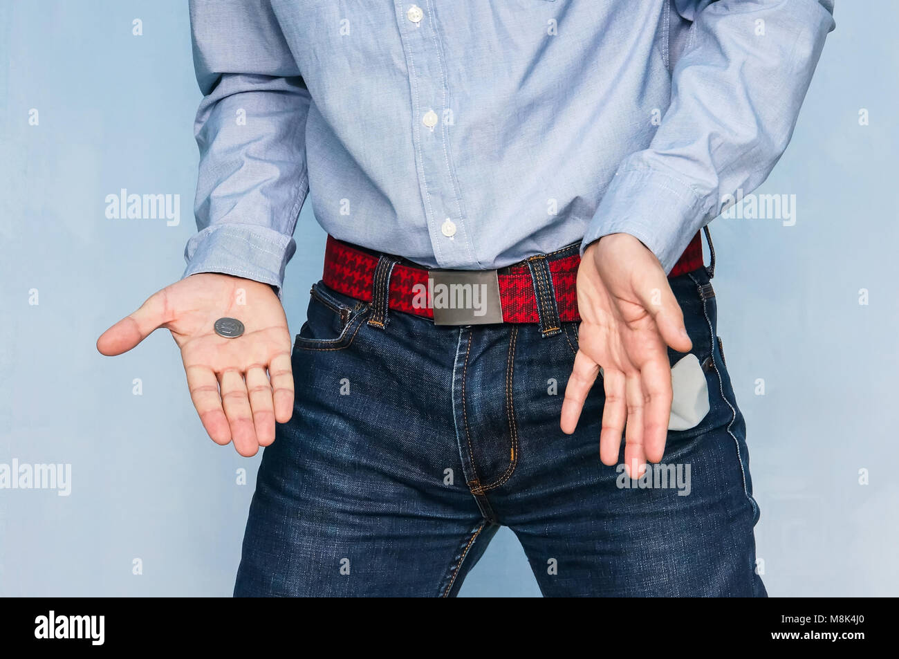 Man showing his empty pocket and holding coin in hand. The guy shows ...