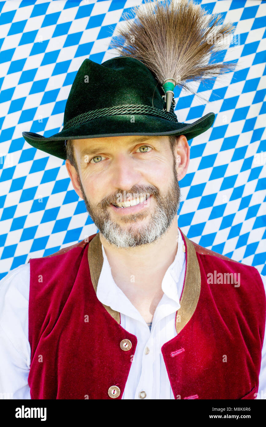 portrait of smiling bavarian man with Gamsbart with blue and white ...