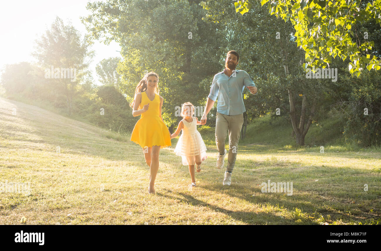 Two happy parents running together with their cute daughter Stock Photo ...