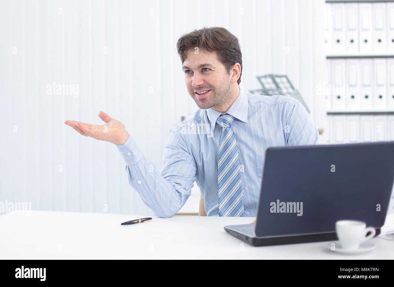 businessman sitting behind a Desk and pointing to copy space Stock ...