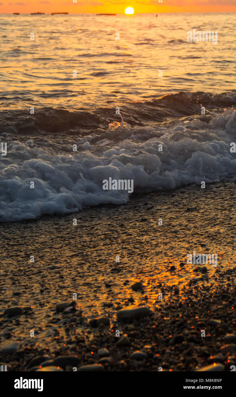 Summer sea sunset on the pebble beach, the sun, waves and clouds ...