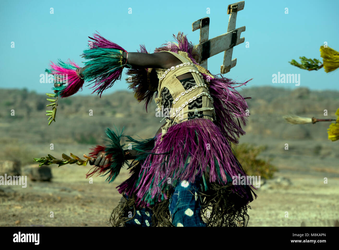 A Dogon man twists and turns while wearing a large mask and headdress ...