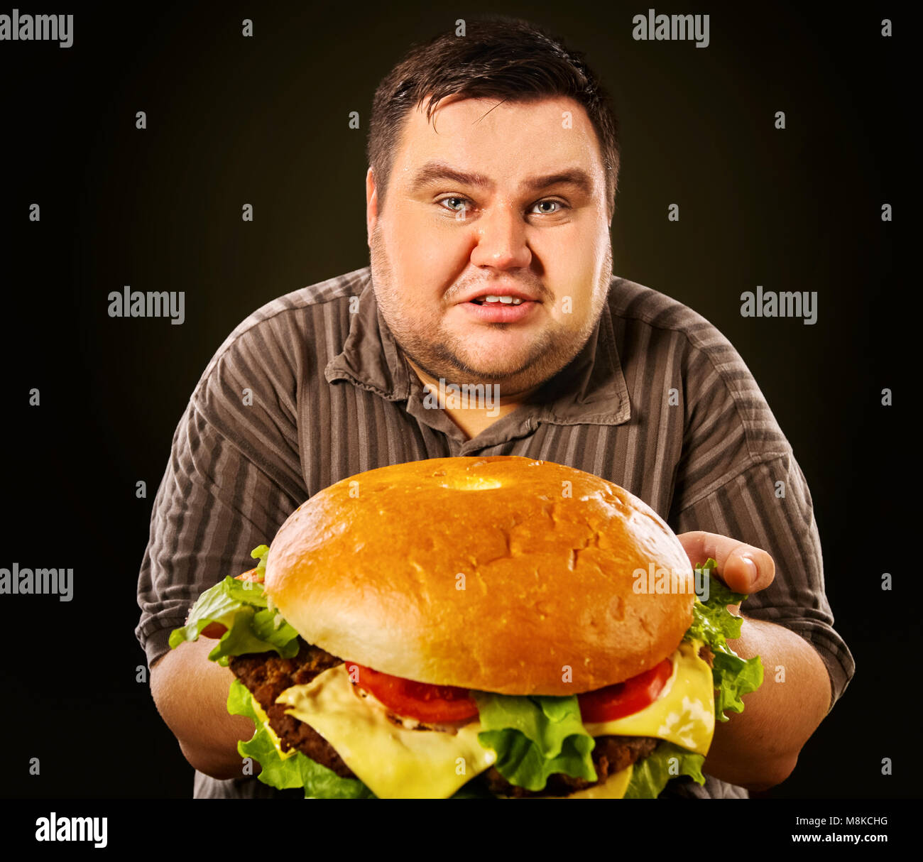 Fat man eating fast food hamberger. Breakfast for overweight person ...