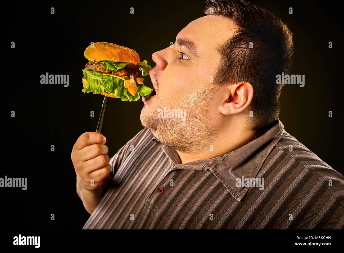Fat man eating fast food hamberger. Breakfast for overweight person ...