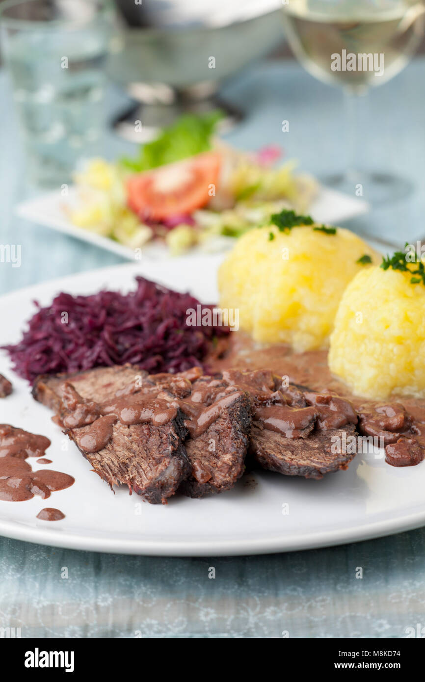german sauerbraten with red cabbage on a plate Stock Photo - Alamy