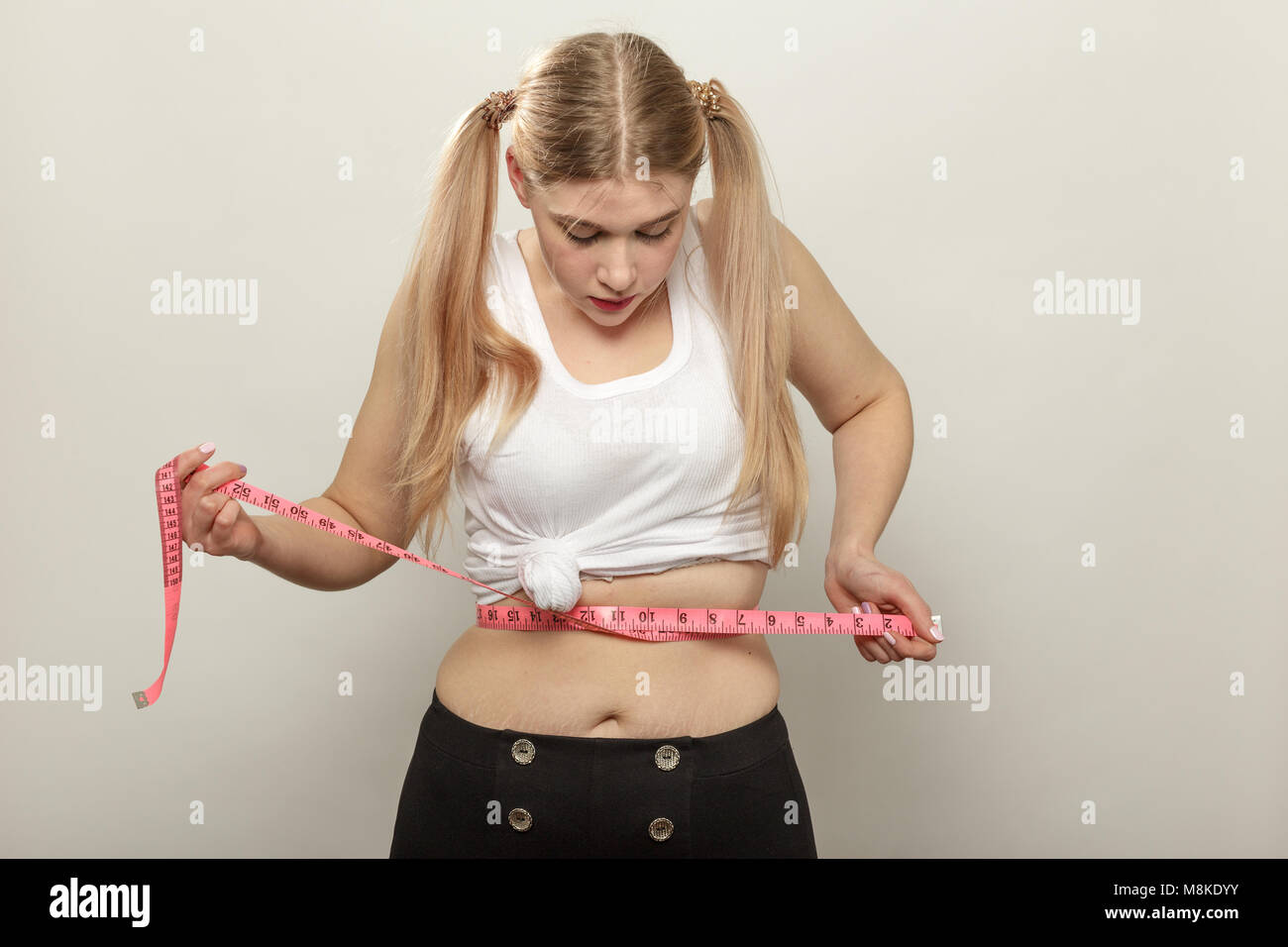 young woman check her stomach fat with tape Stock Photo - Alamy