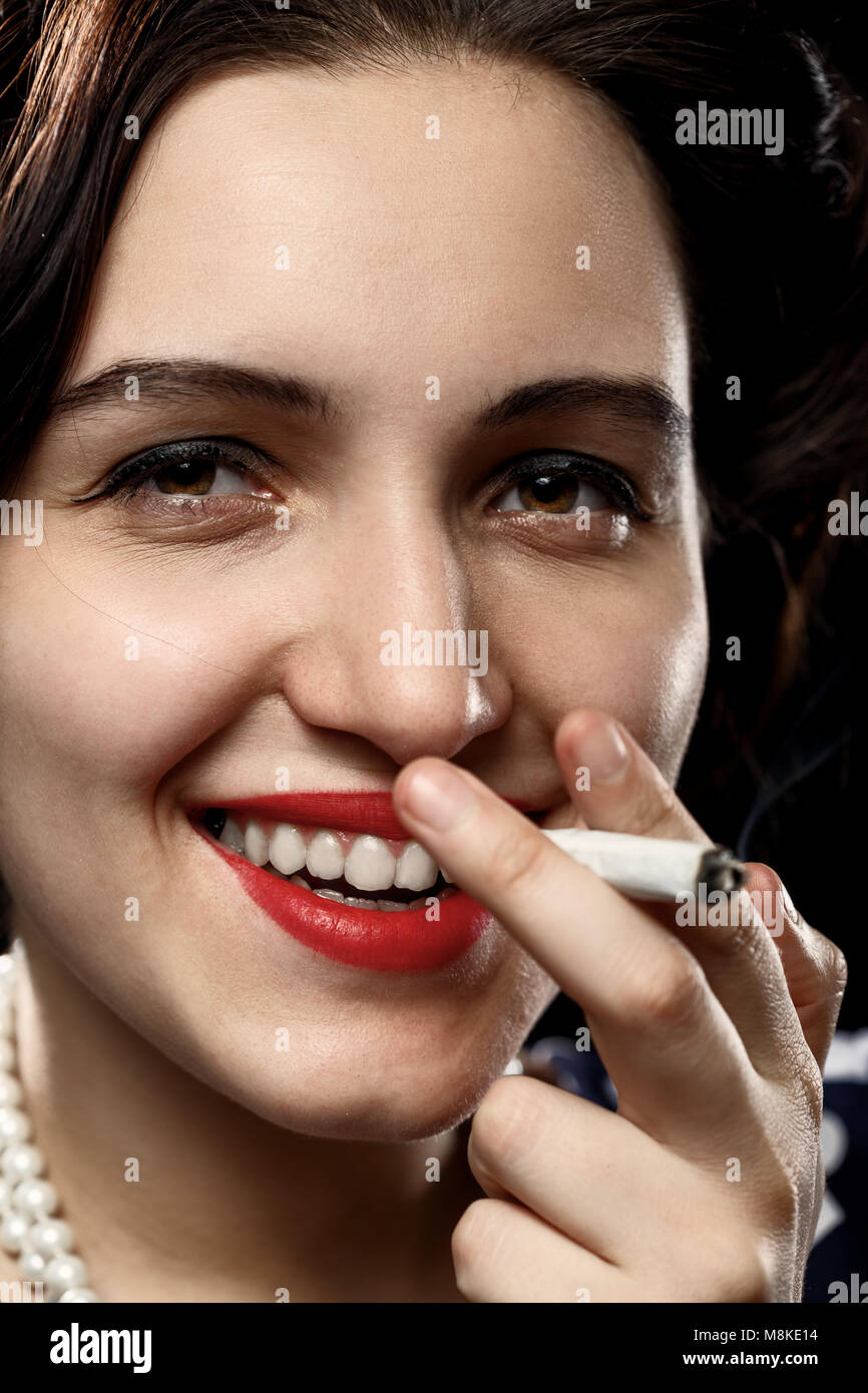 blond young woman smoking joint on black background Stock Photo - Alamy