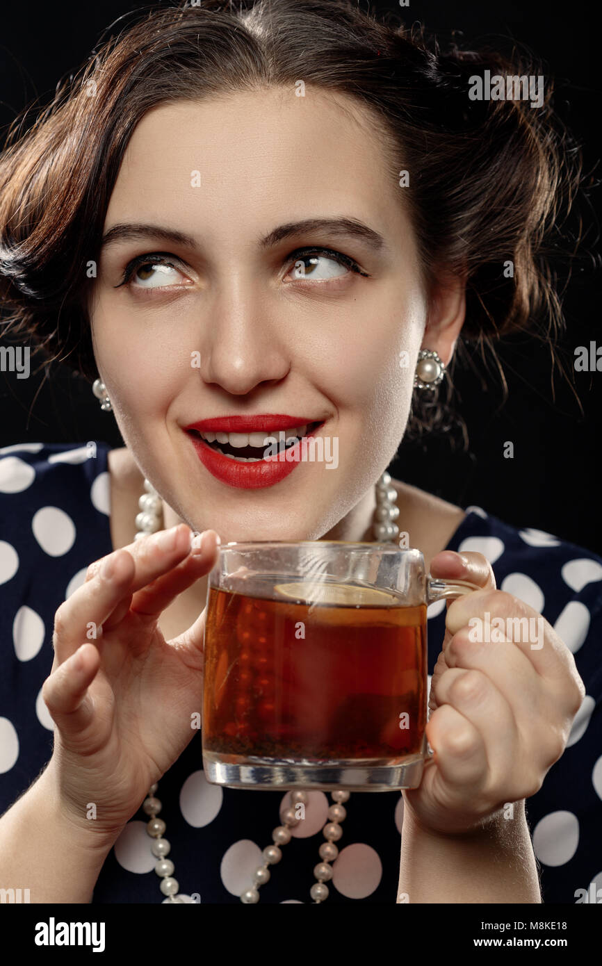 beautiful pinup woman with cup of tea on black background Stock Photo ...