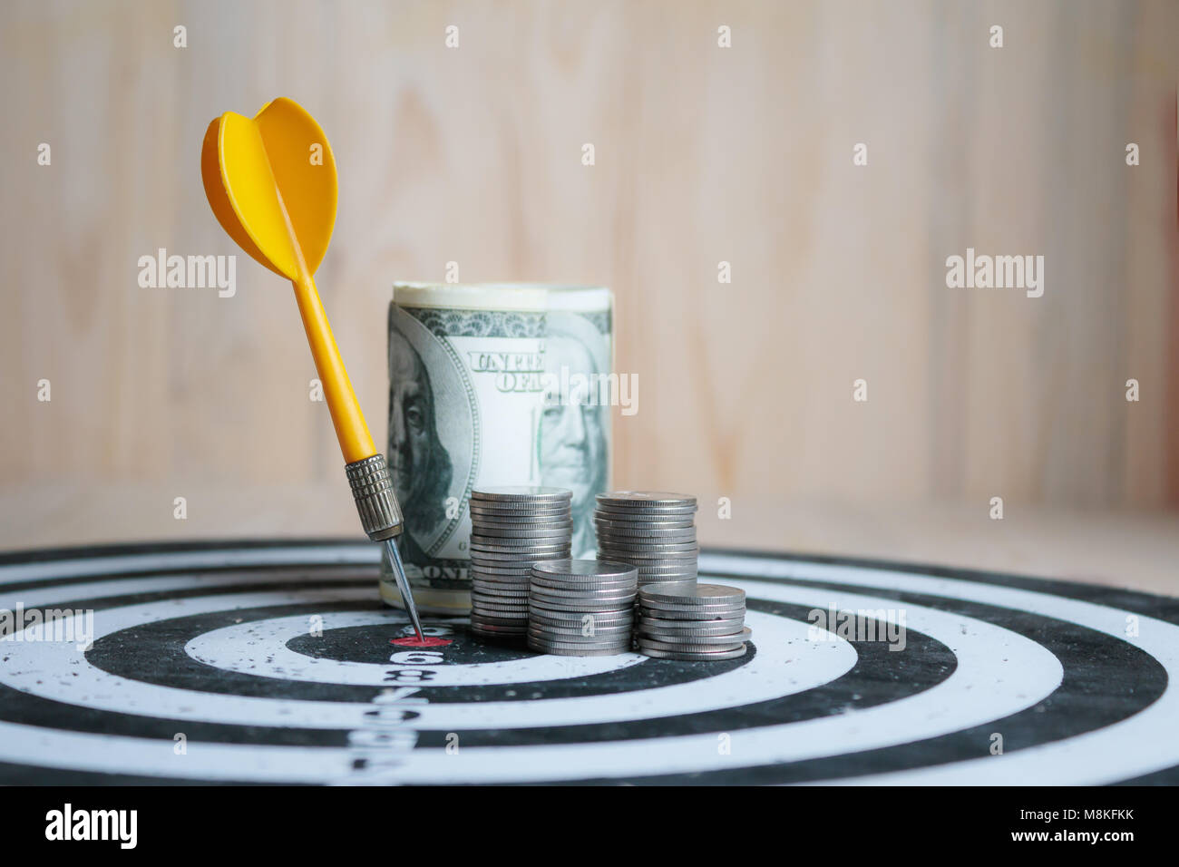 Yellow dart arrow hit the center target of dartboard and money coin ...