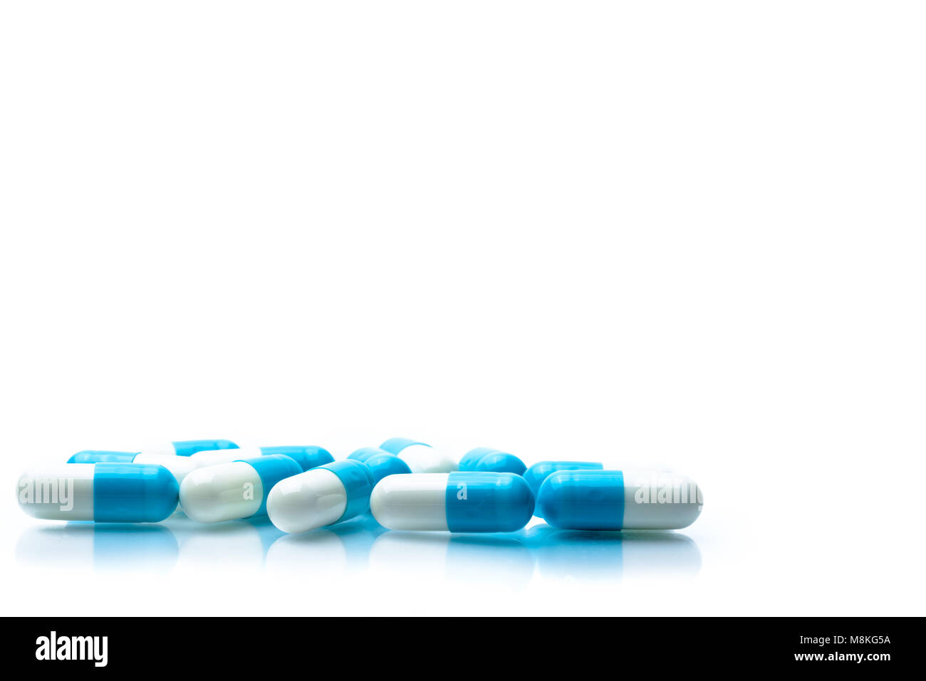 Pile of blue and white capsules pills isolated on white background with ...