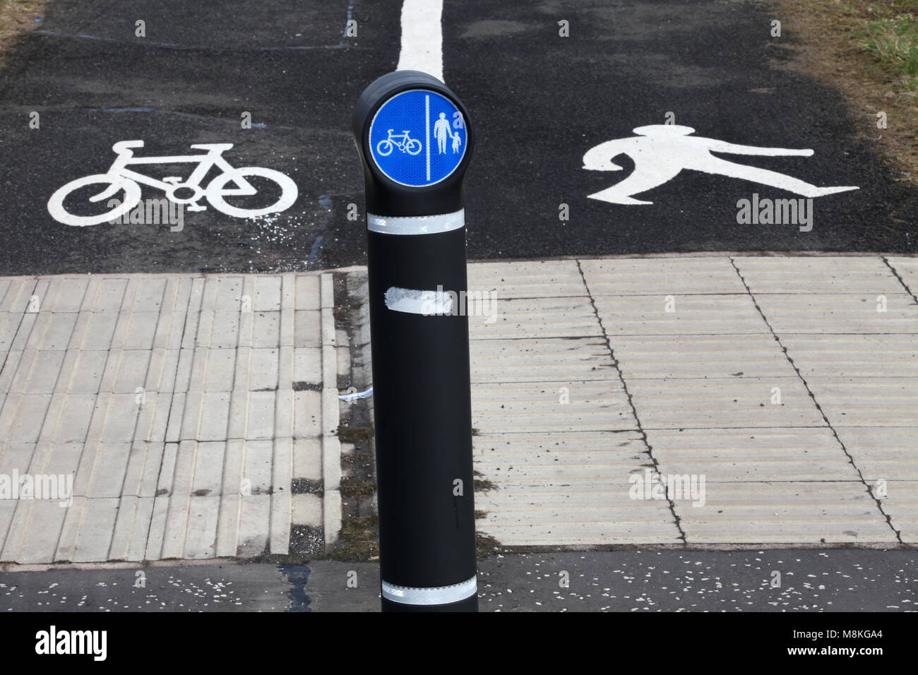 A post and painted symbols showing the lane split between cyclists and ...
