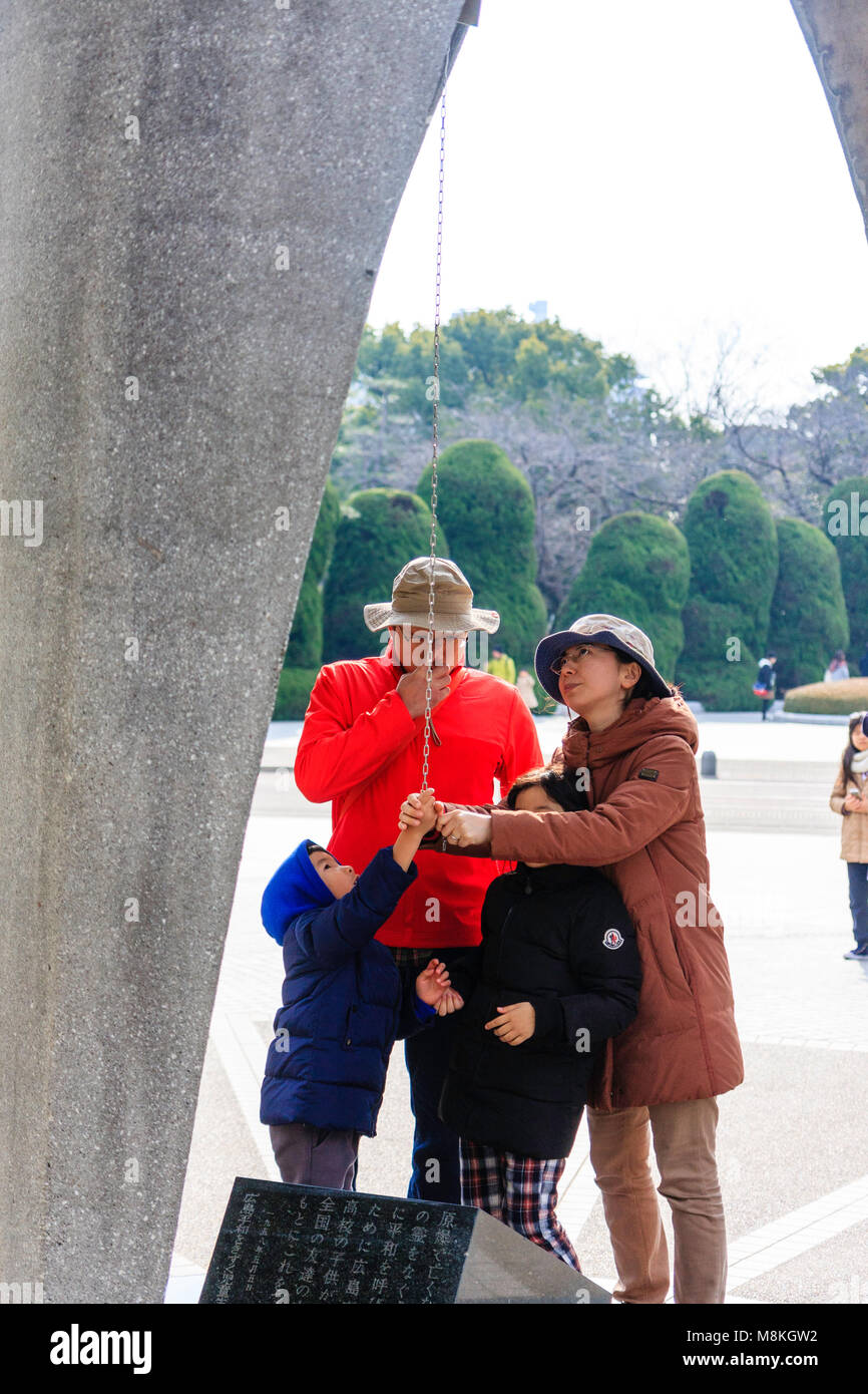 Japan, Hiroshima. Family with children ringing the bell at the Children ...