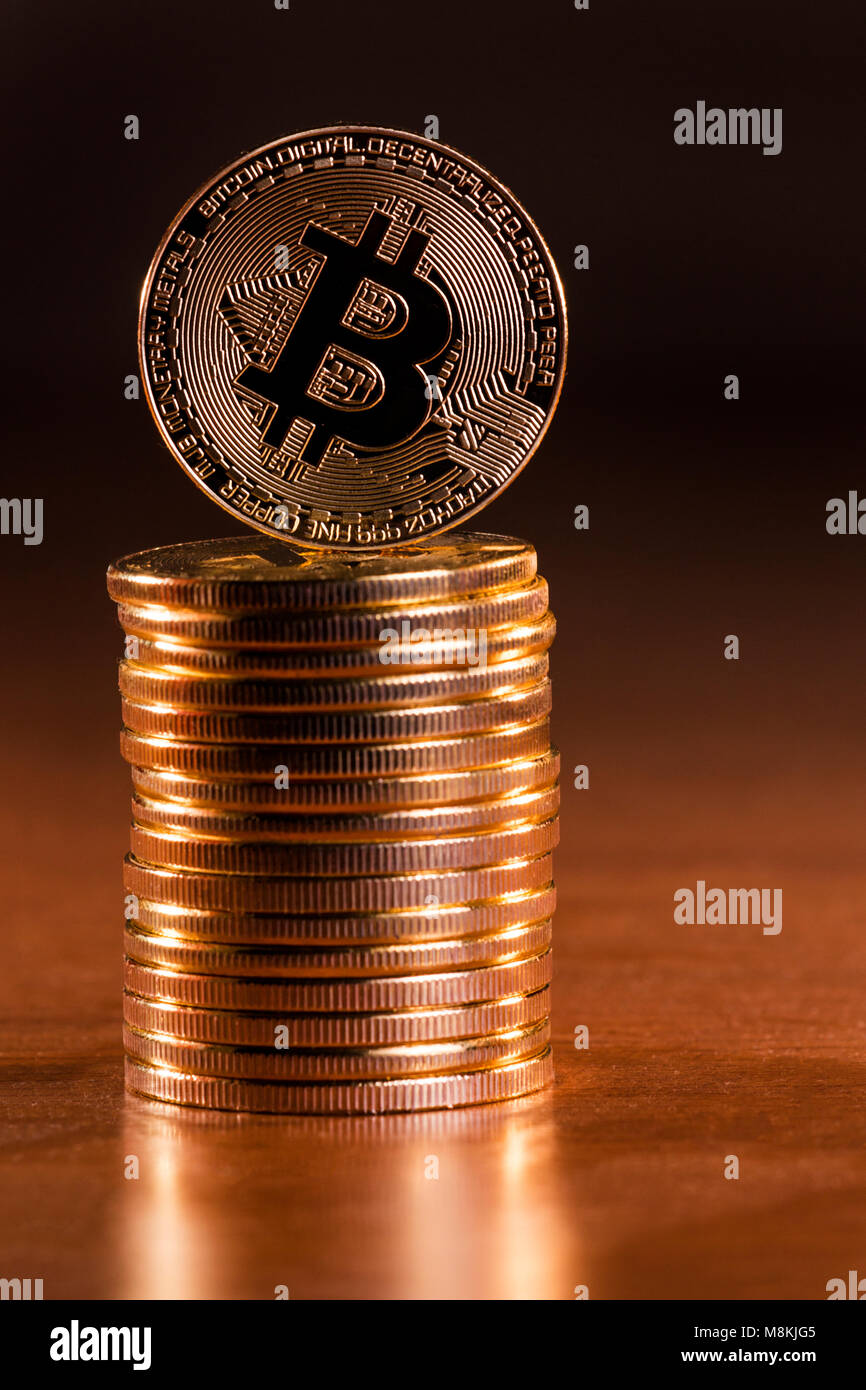 several golden bitcoins stacked on top of wooden table Stock Photo - Alamy
