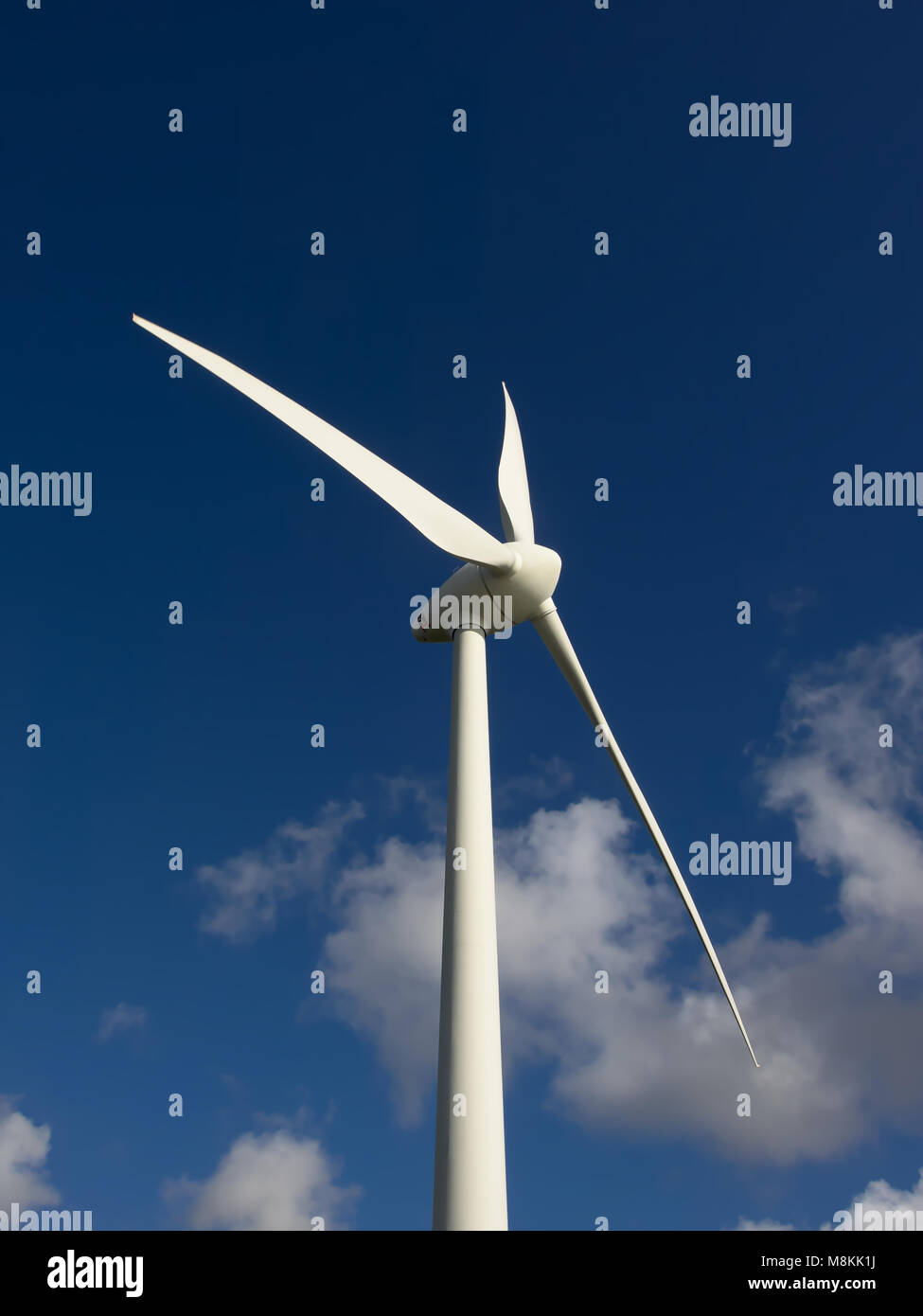 Windmill in the sun against blue sky with soft clouds, low perspective ...