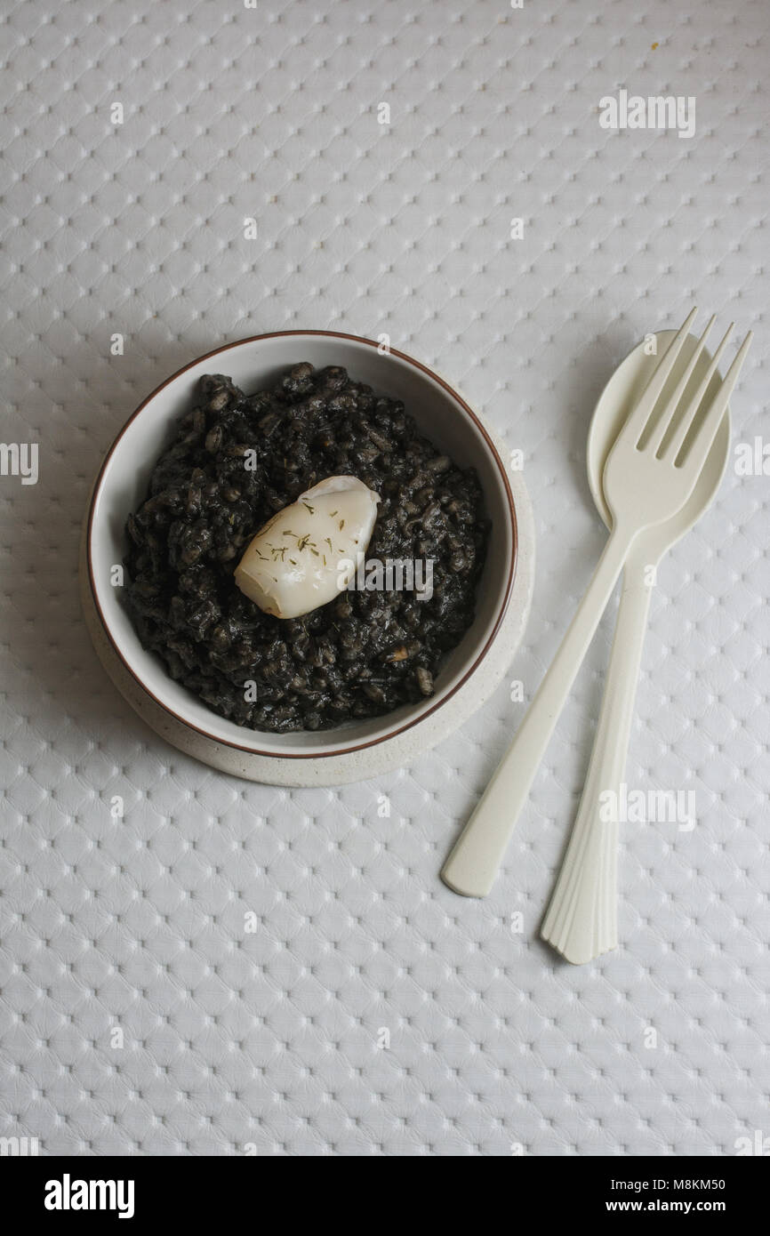 Black rice with cuttlefish, on black cement dish and grunge background ...