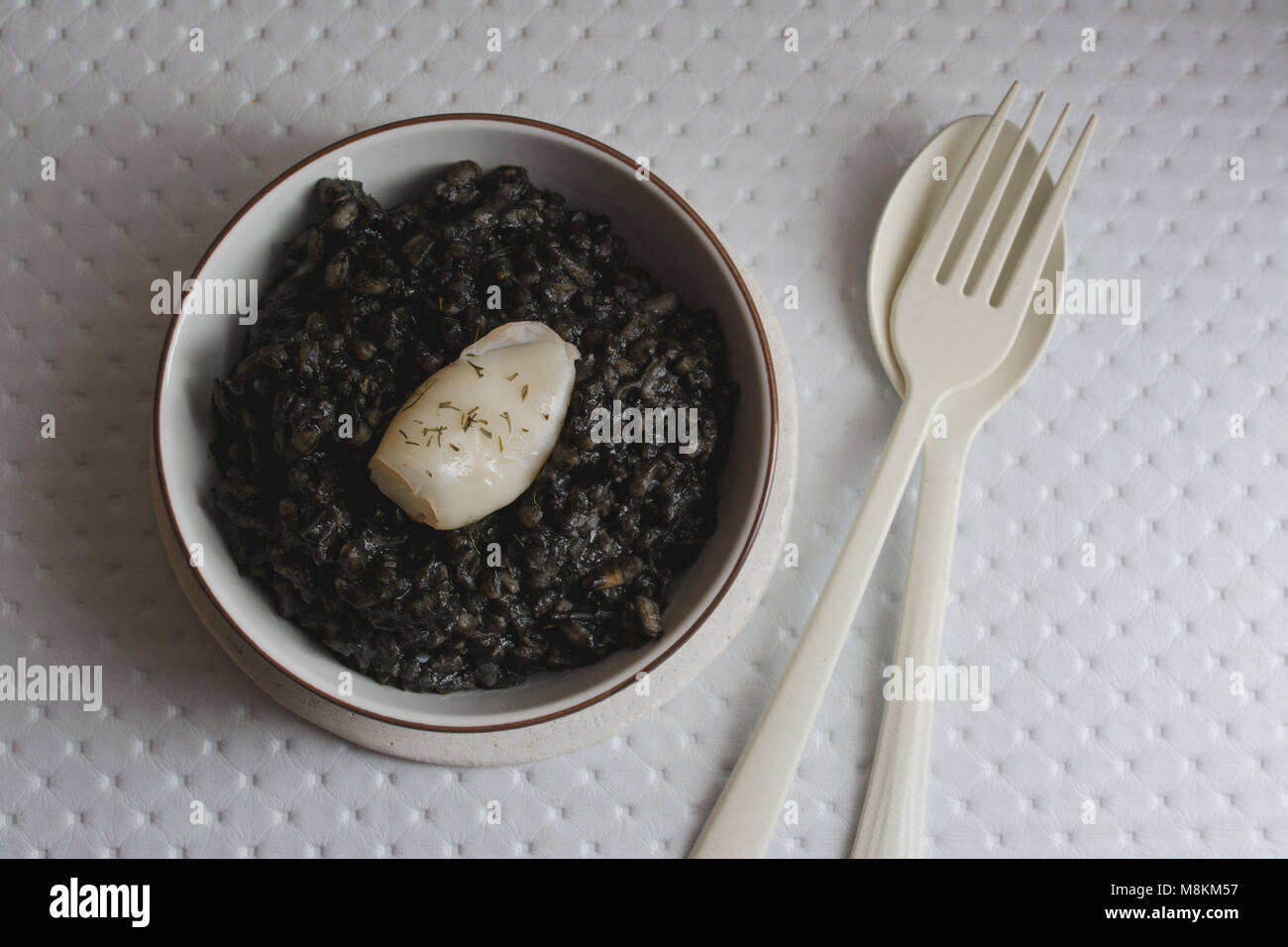 Black rice with cuttlefish, on black cement dish and grunge background ...