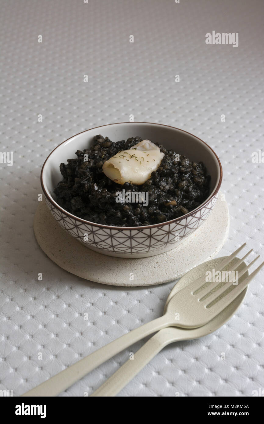 Black rice with cuttlefish, on black cement dish and grunge background ...