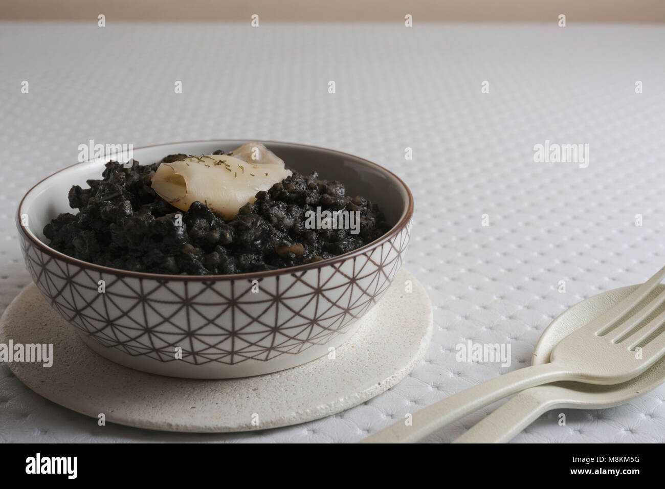 Black rice with cuttlefish, on black cement dish and grunge background ...