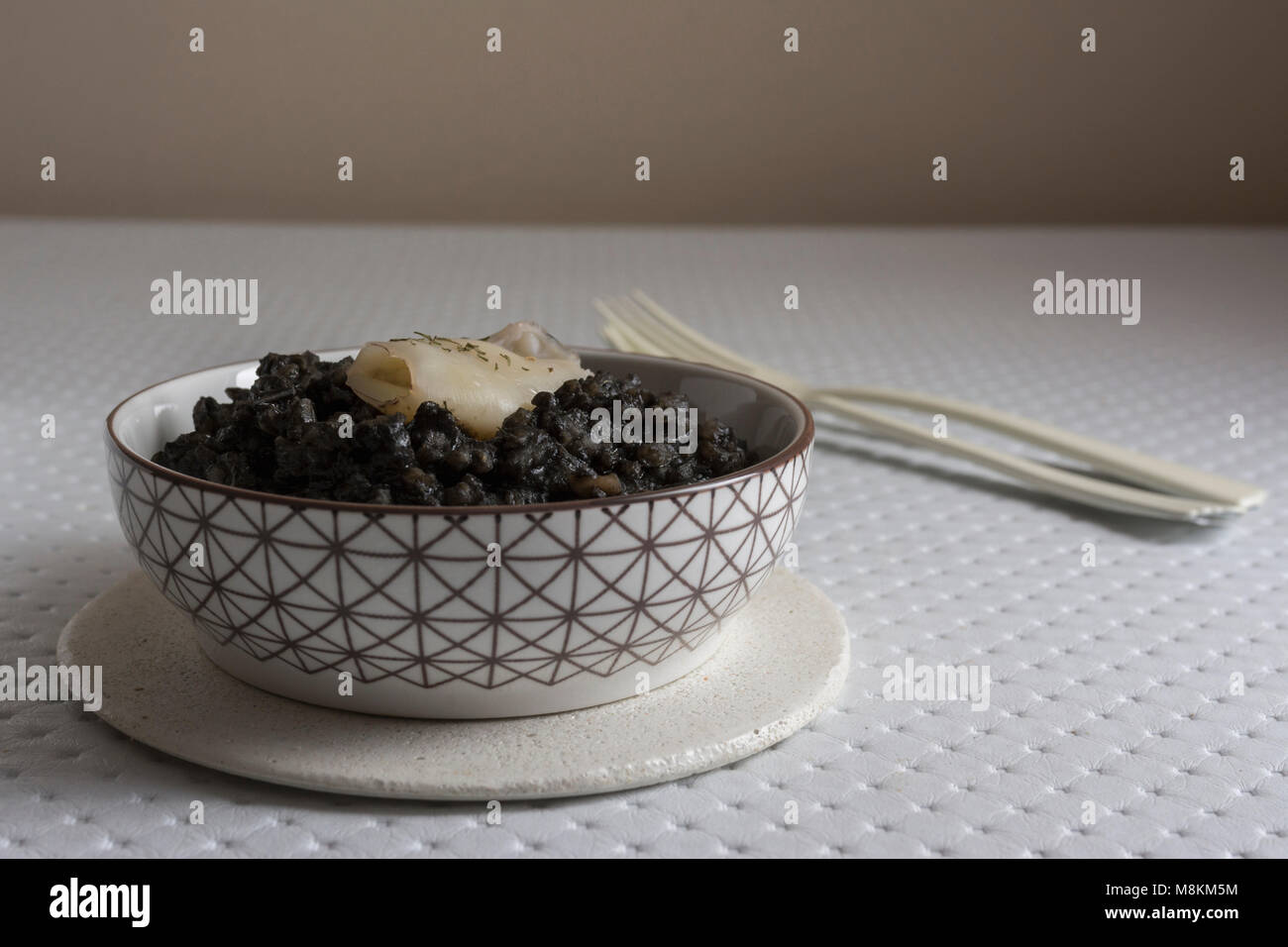 Black rice with cuttlefish, on black cement dish and grunge background ...