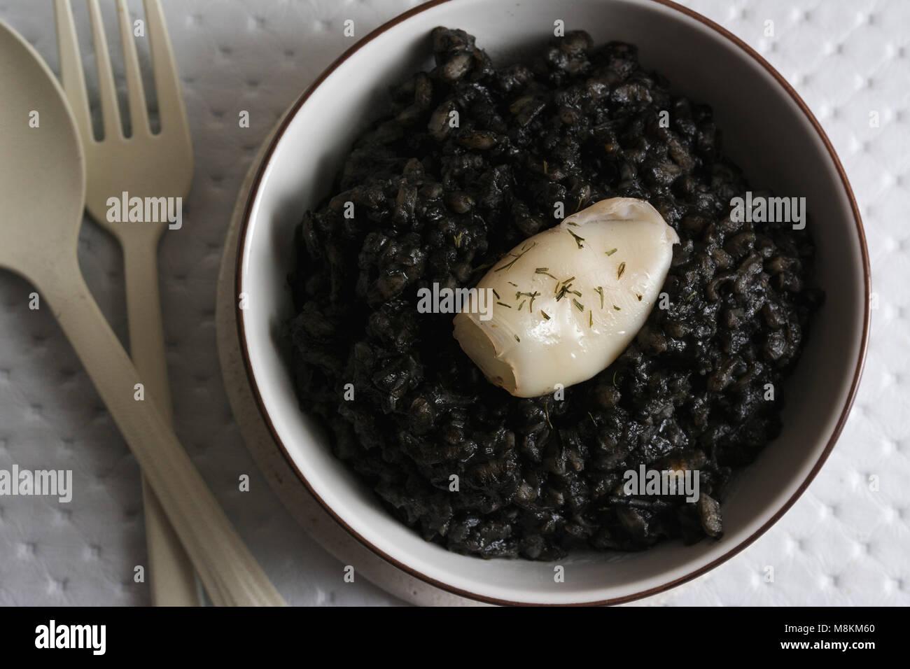 Black rice with cuttlefish, on black cement dish and grunge background ...