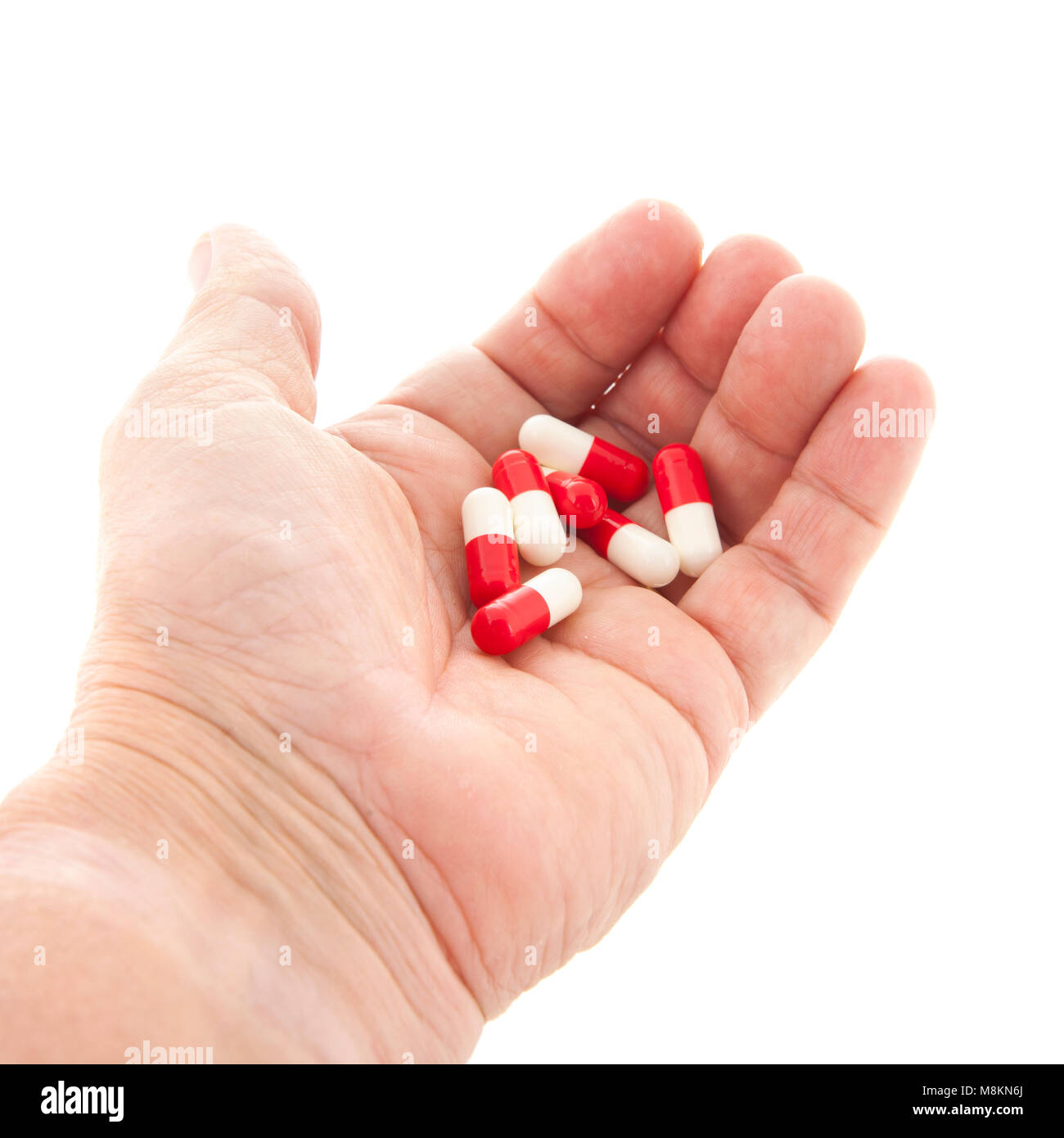 Capsules in red and white in old hand isolated over white background ...