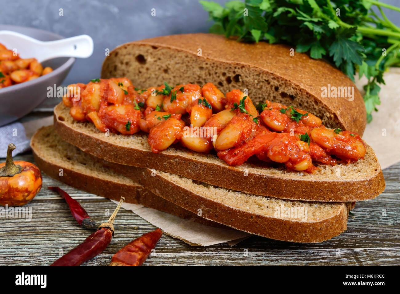 A piece of rye bread with beans. Stewed beans in tomato sauce with ...