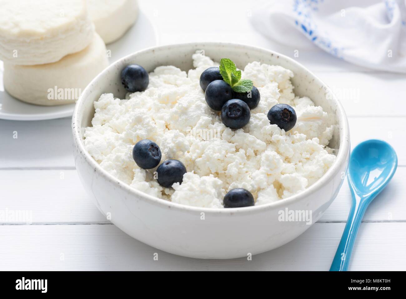 Cottage cheese, farmers cheese or tvorog in white bowl on white wooden ...