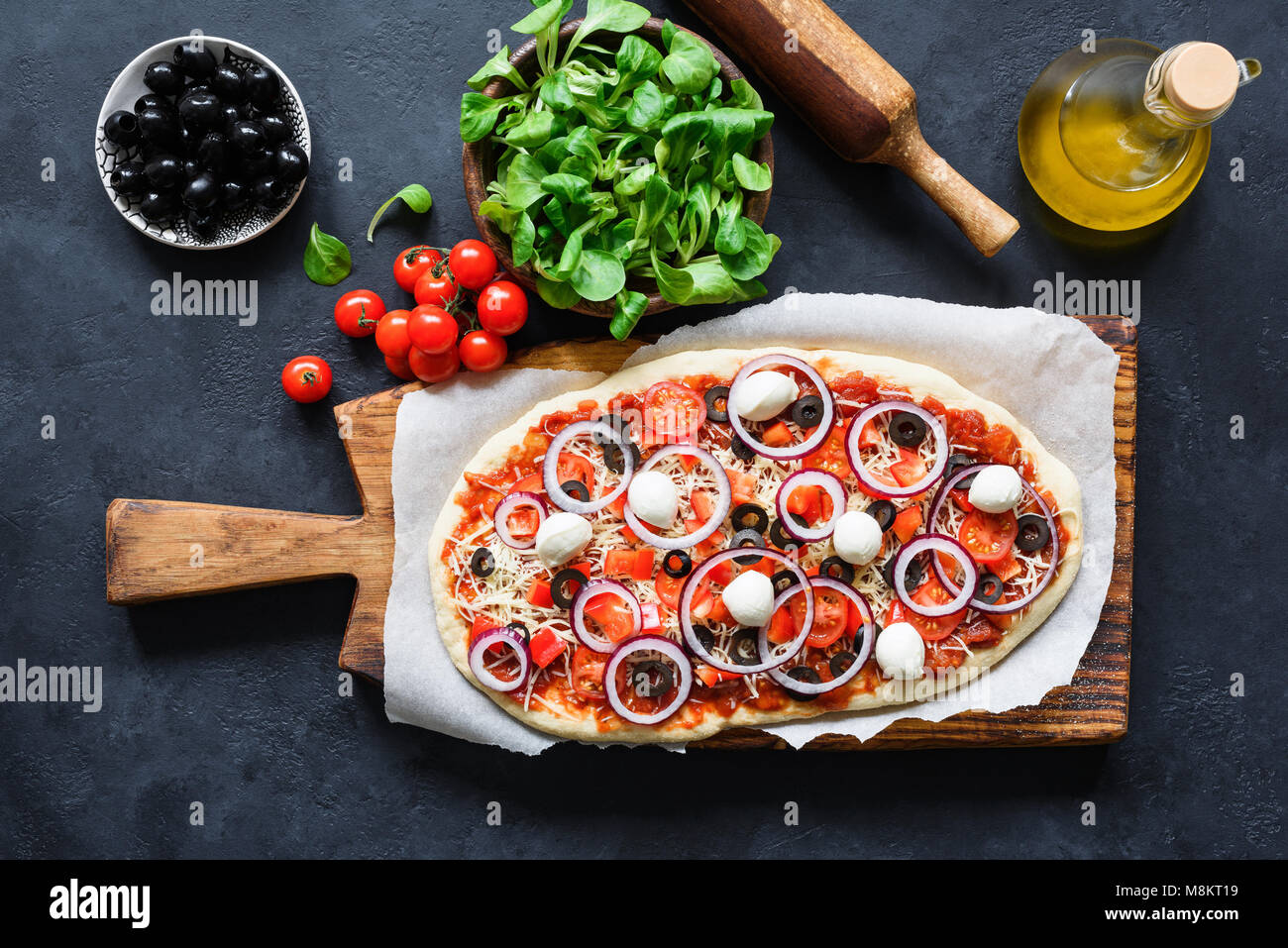 Homemade pizza preparation. Pizza ingredients on dark background, table ...