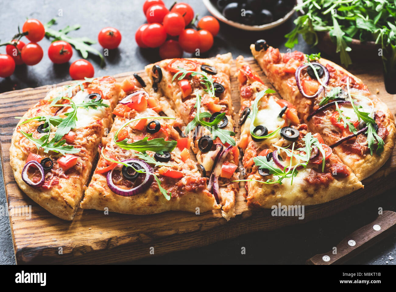 Homemade flatbread pizza sliced on wooden cutting board. Selective ...