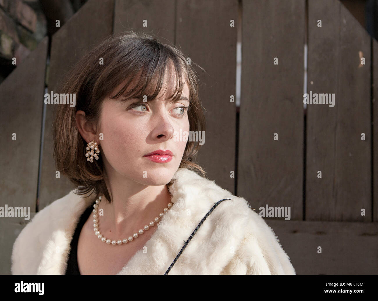 A well dressed woman, standing alone outside, with a concerned look on ...