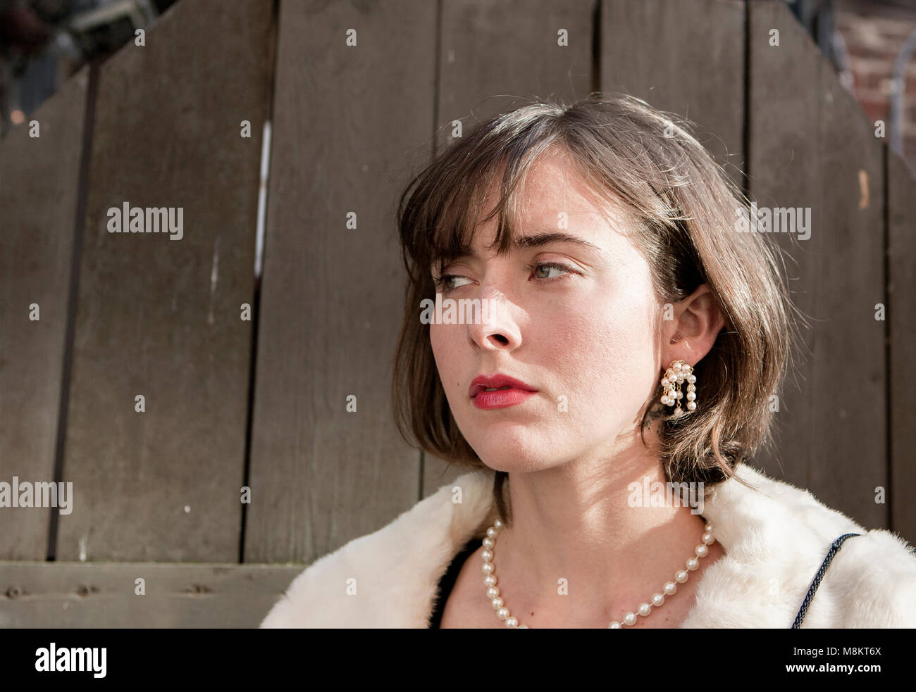 A well dressed woman, standing alone outside, with a concerned look on ...