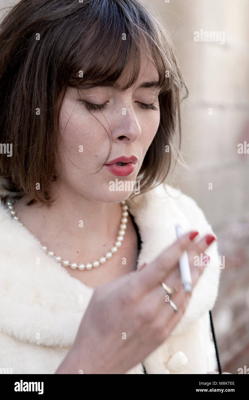 A well dressed woman wearing red lipstick, smoking a cigarette Stock ...